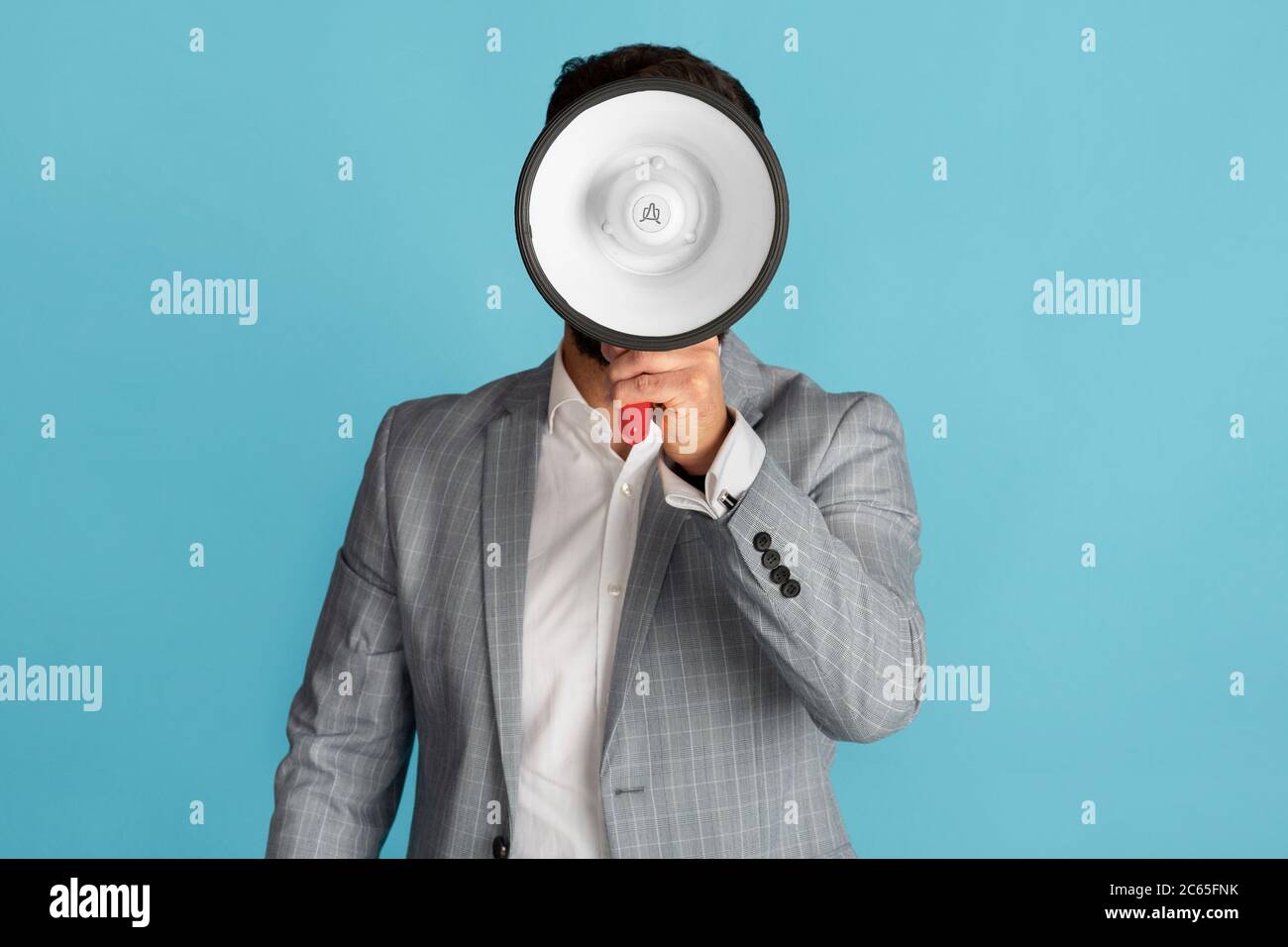 Businessman holding megaphone in front of his face on blue background ...