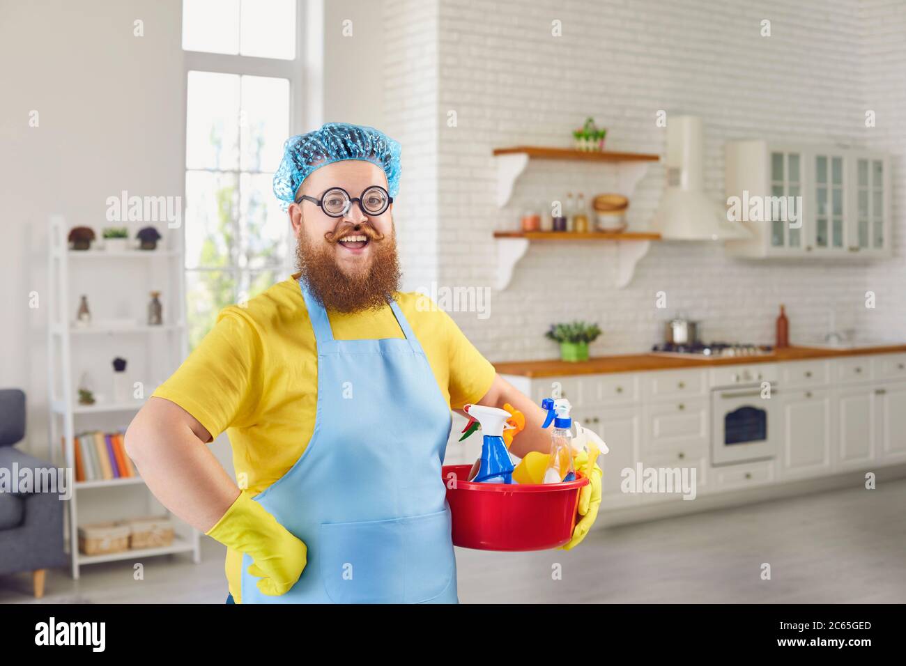 Funny fat man with a beard in an apron cleans the room in the house ...