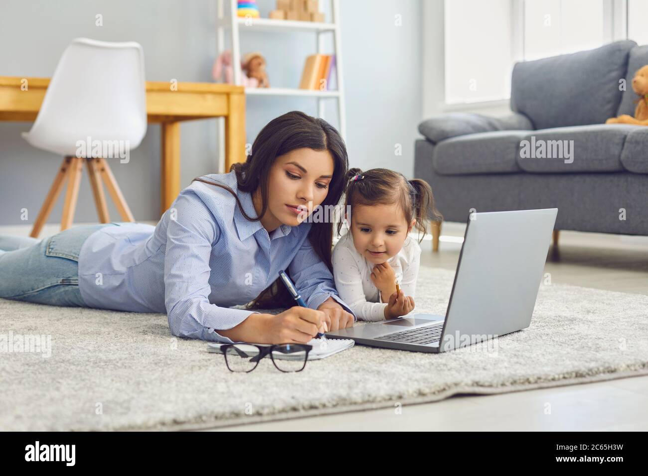 Work online. Woman working from home using laptop computer lying on ...