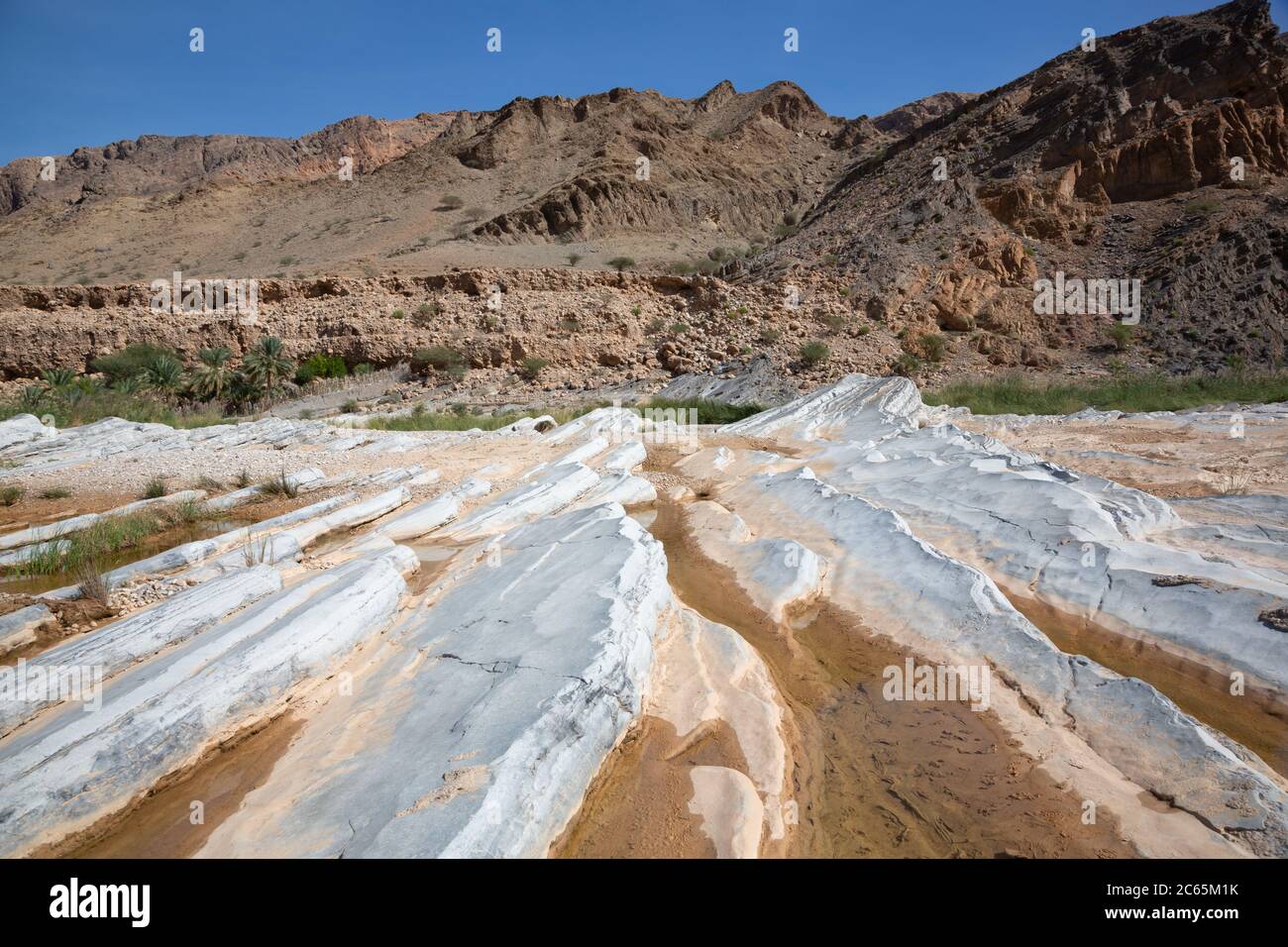 Slanted limestone benches in front of mountain range in Oman's Wadi ...