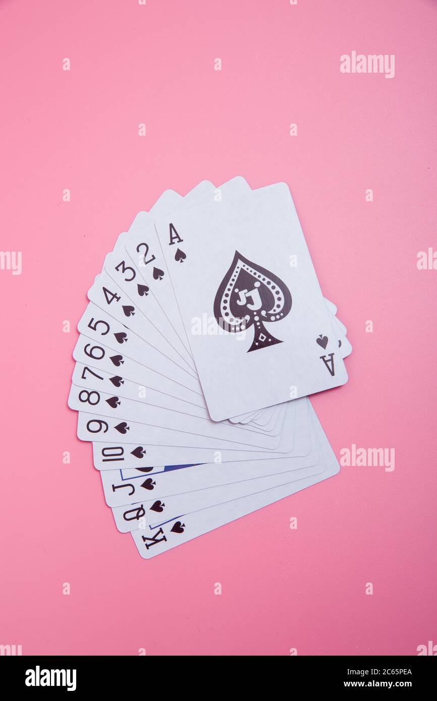Expanded playing cards on pink background Stock Photo - Alamy
