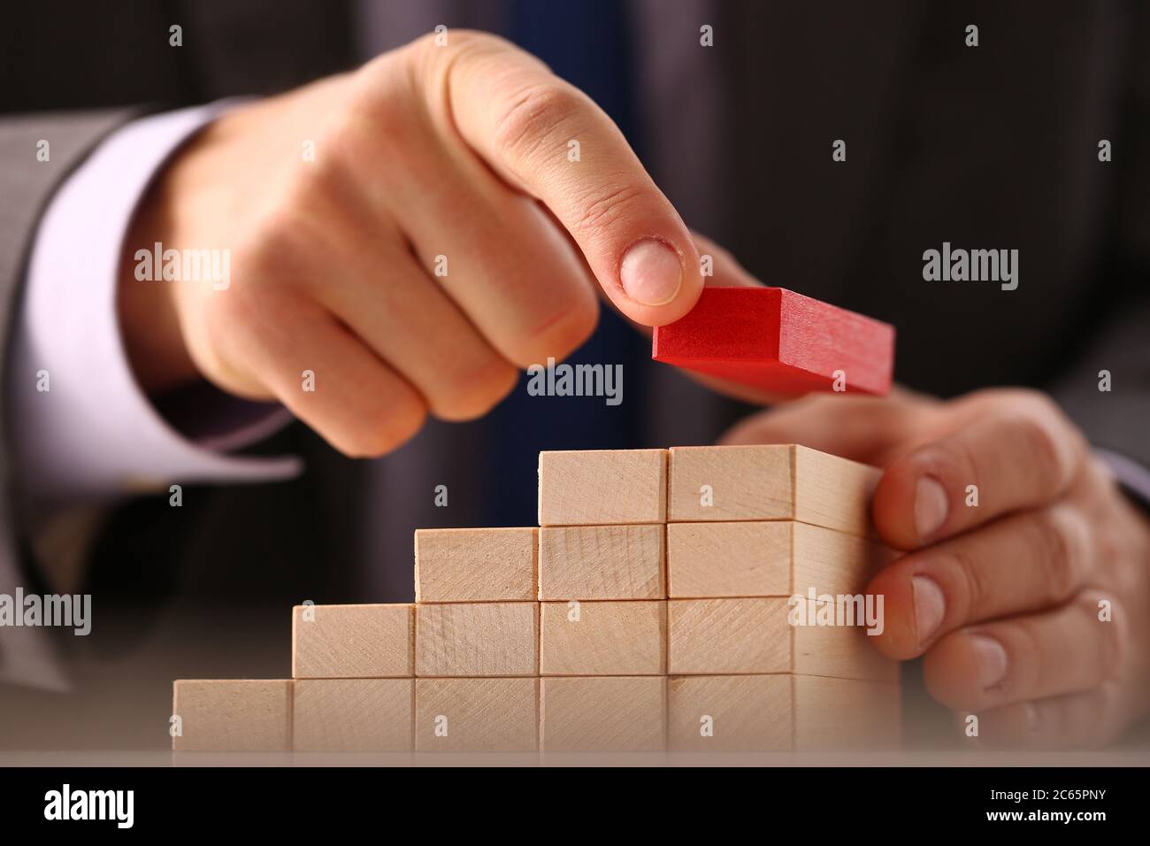 Man arranging wood block and stacking as tower by hand Stock Photo - Alamy