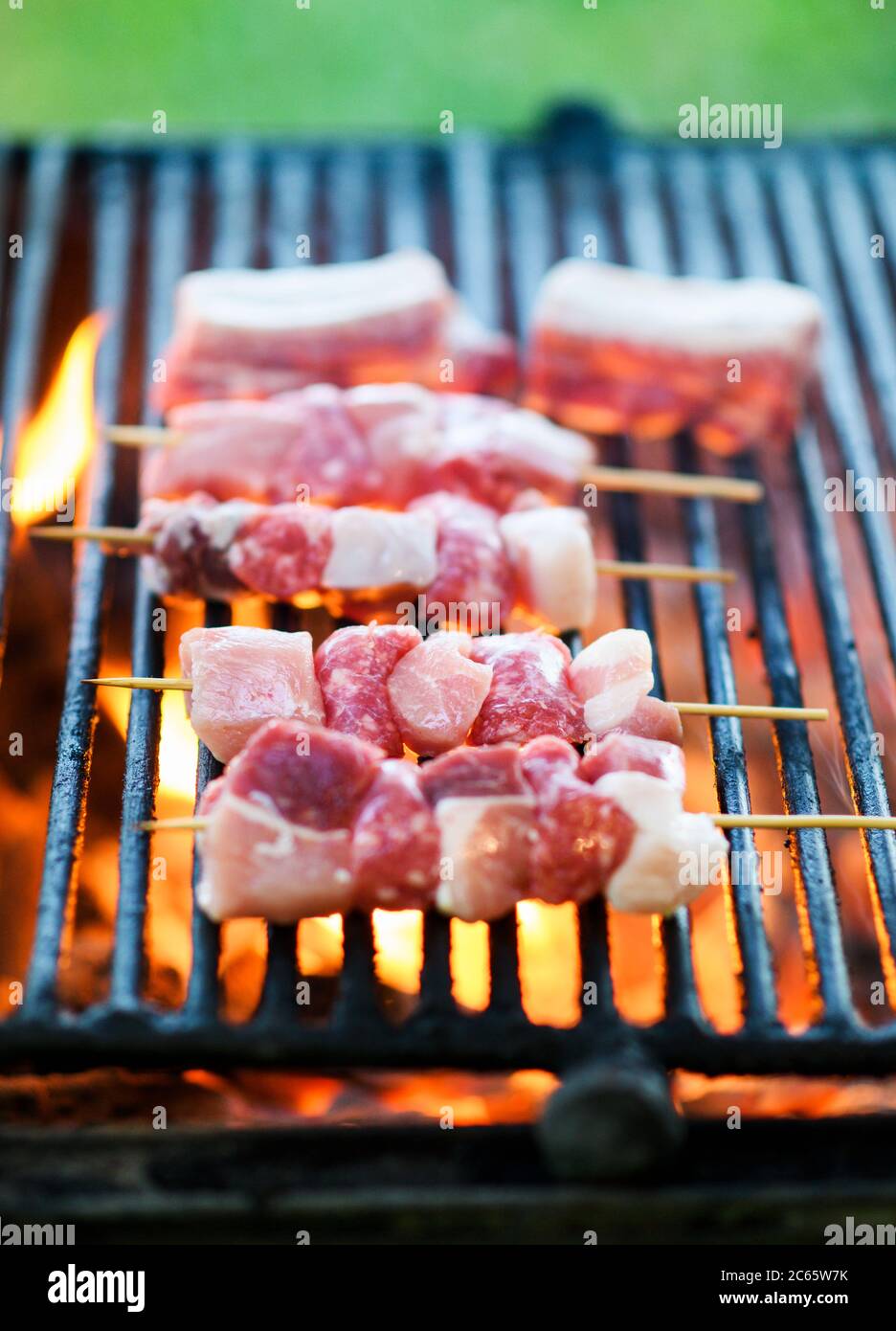 Raw beef skewers grilling over a BBQ fire with glowing hot coals in ...