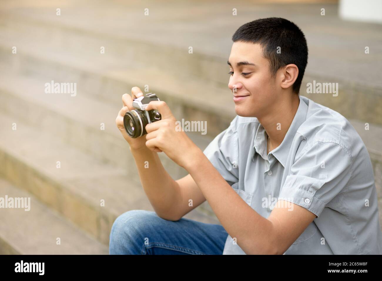 Young teenage boy smiling as he checks the photo on the back of his ...