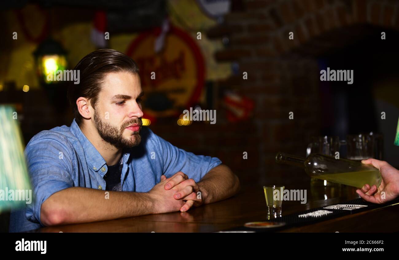 Guy waits for shot or liqueur at bar counter. Macho with shot or ...