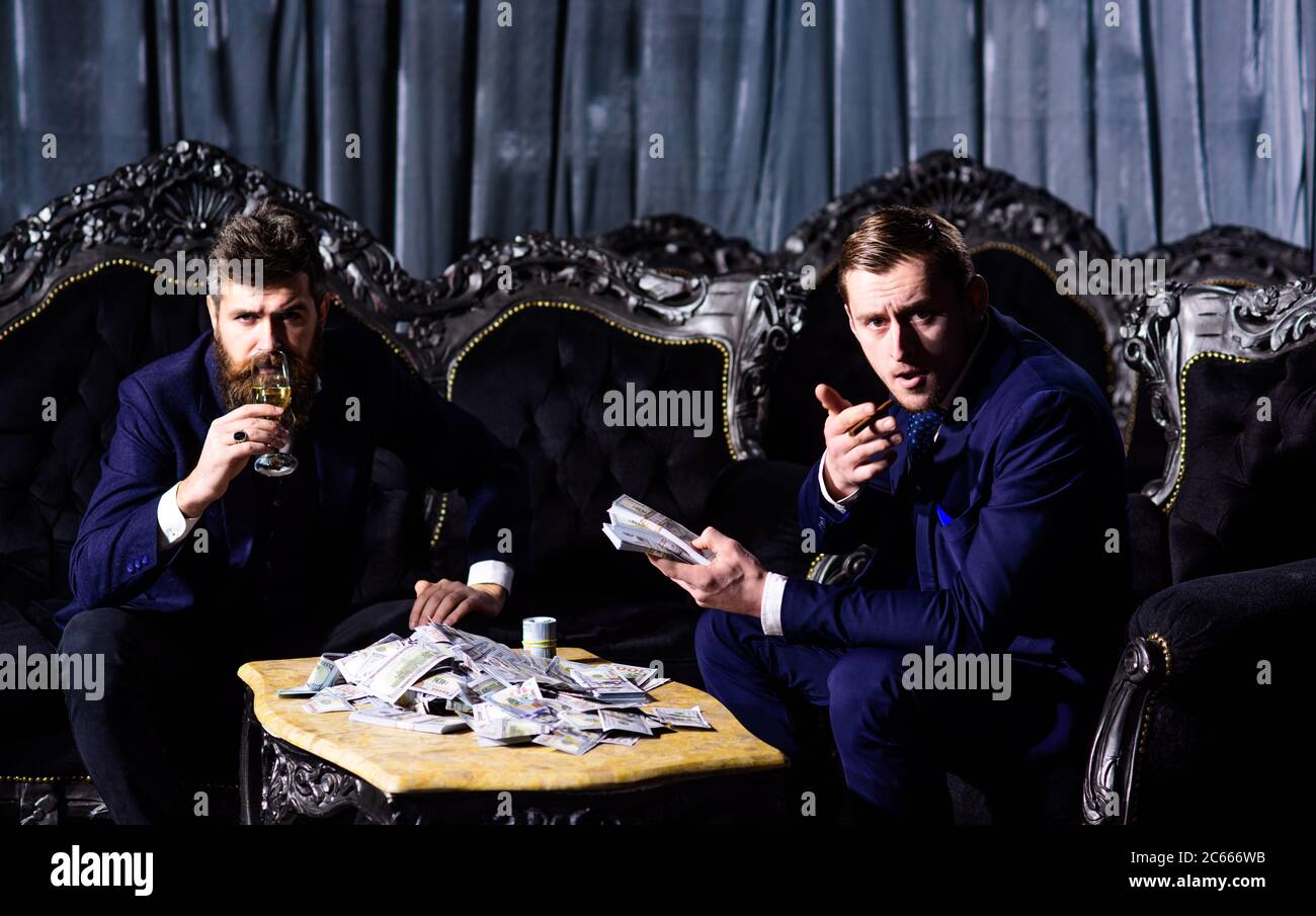 Business partners with serious and surprised faces hold dollars and ...