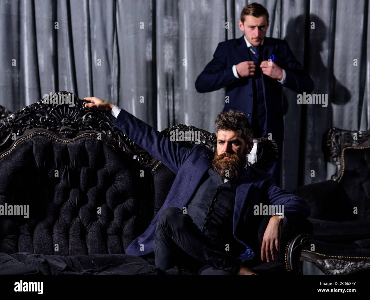 Bearded man with confident face and his bodyguard in classic interior ...