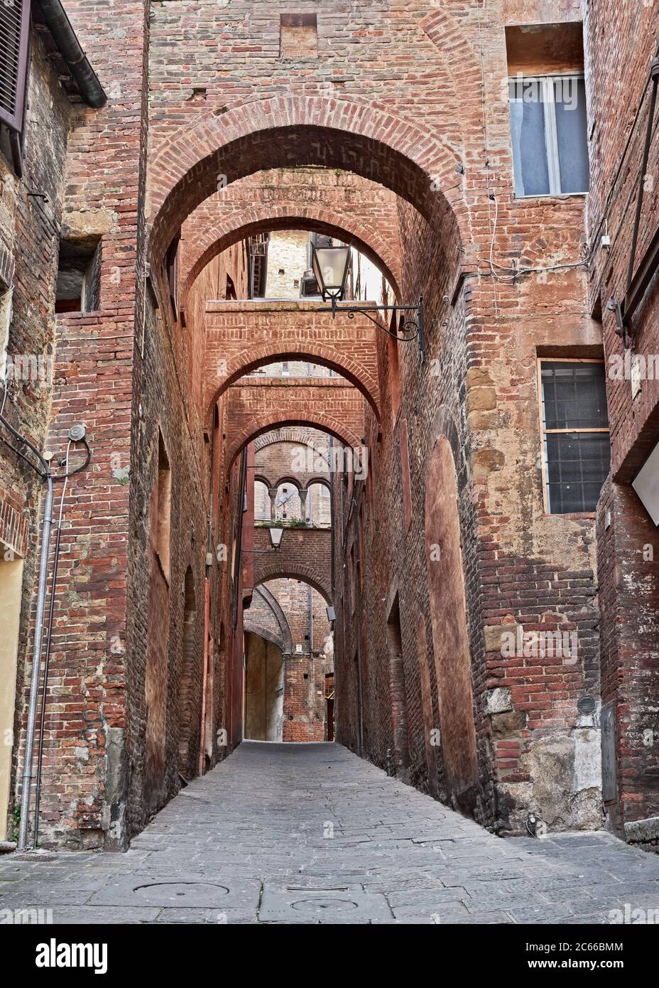 Siena, Tuscany, Italy: ancient alley with arches in the old town of the ...