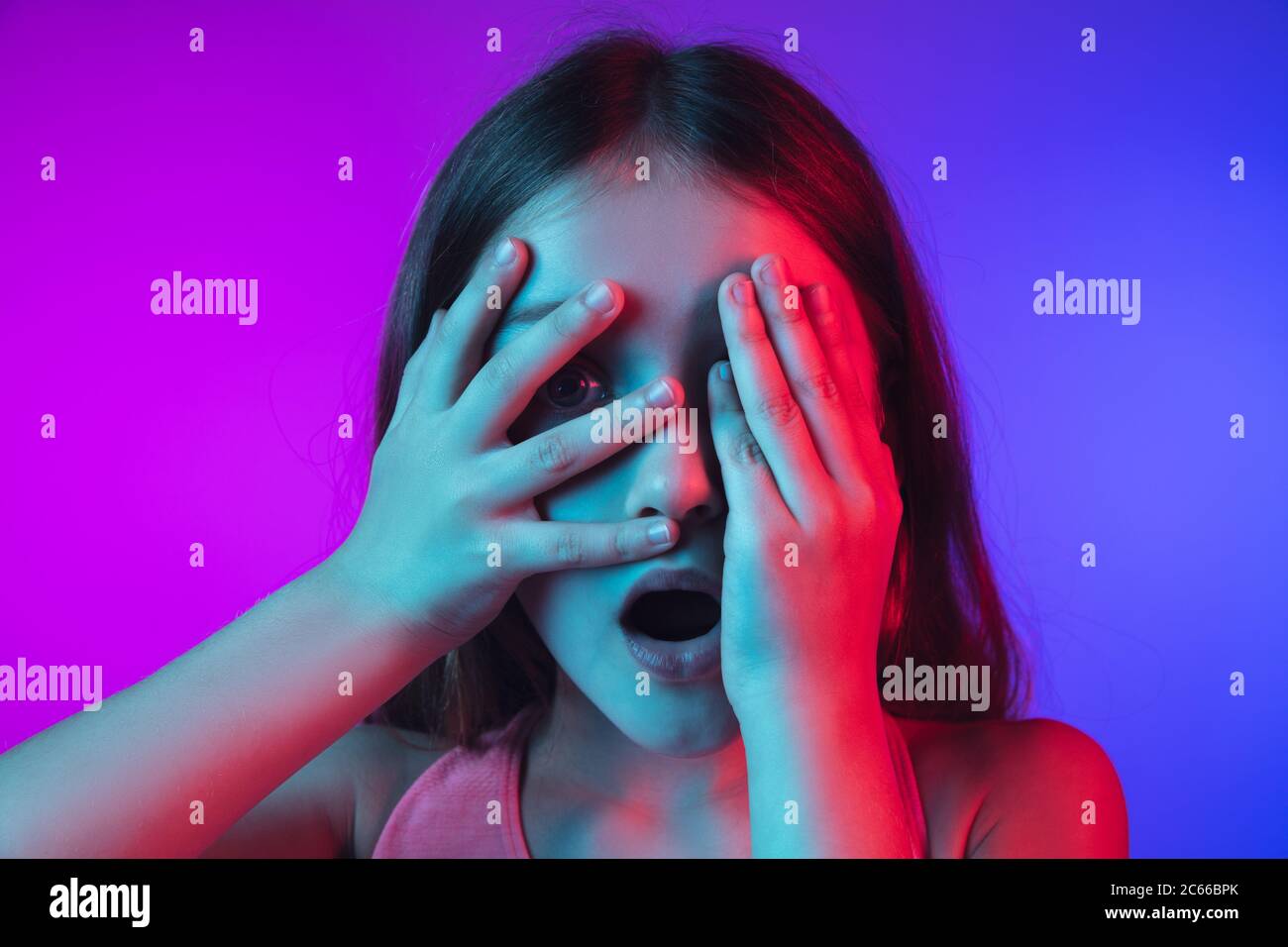 Shocked, scared hiding face. Little girl's portrait on gradient pink ...