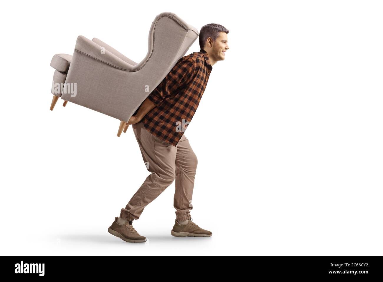 Young man carrying an armchair on his back isolated on white background ...