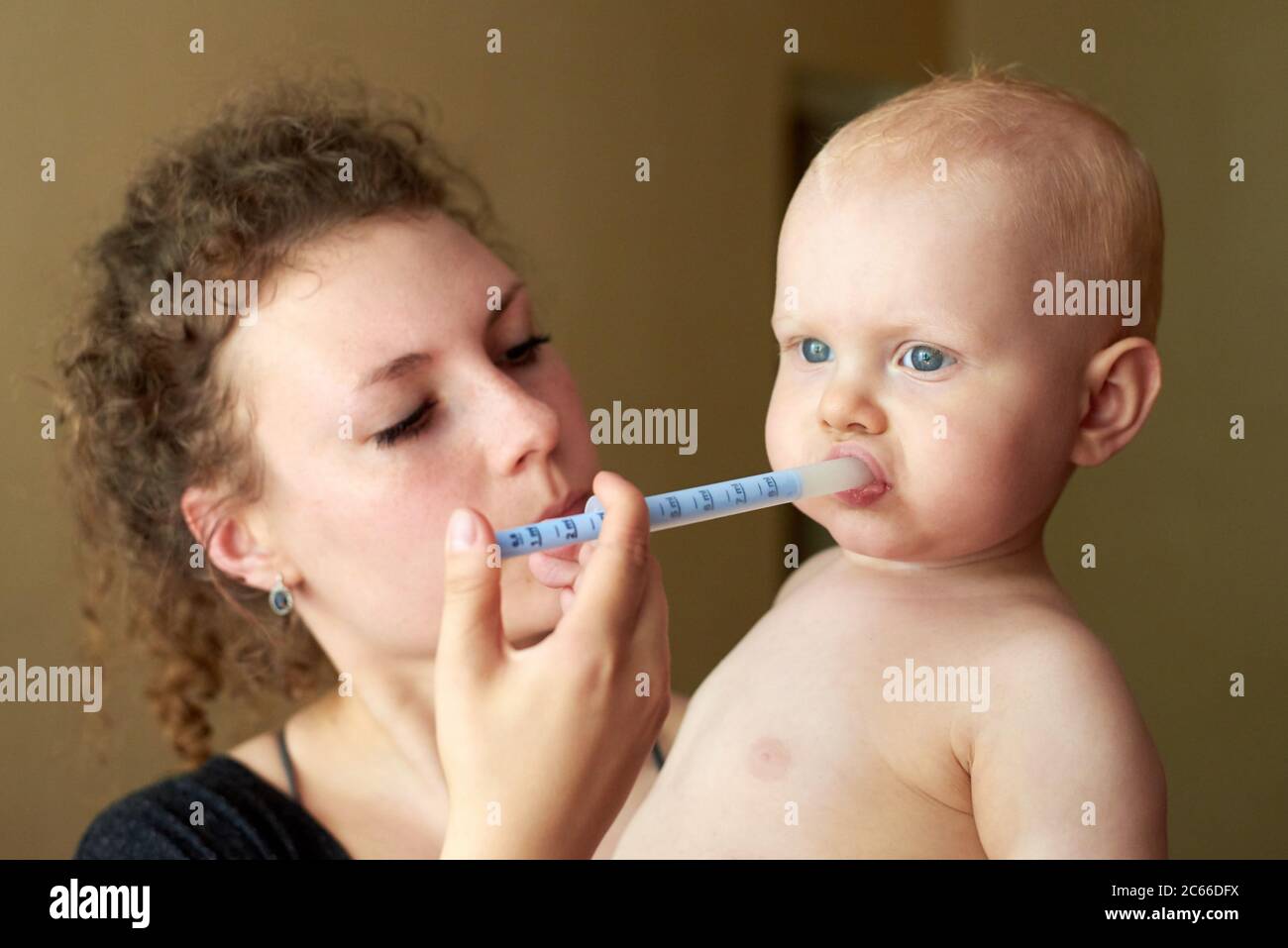 Mom gives her little child medicine through a syringe Stock Photo - Alamy