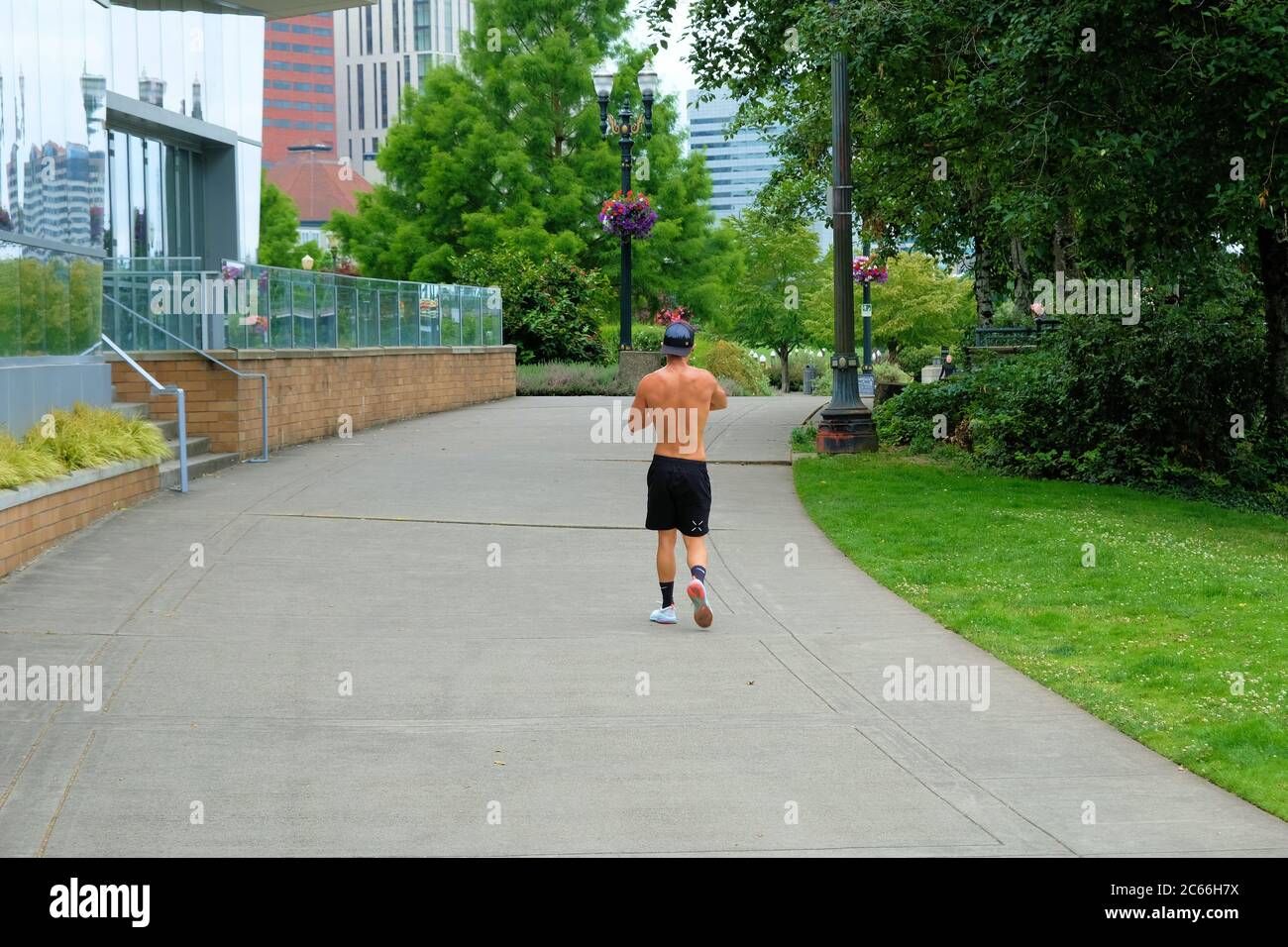 Shirtless man walking away on concrete walkway exercising in black ...