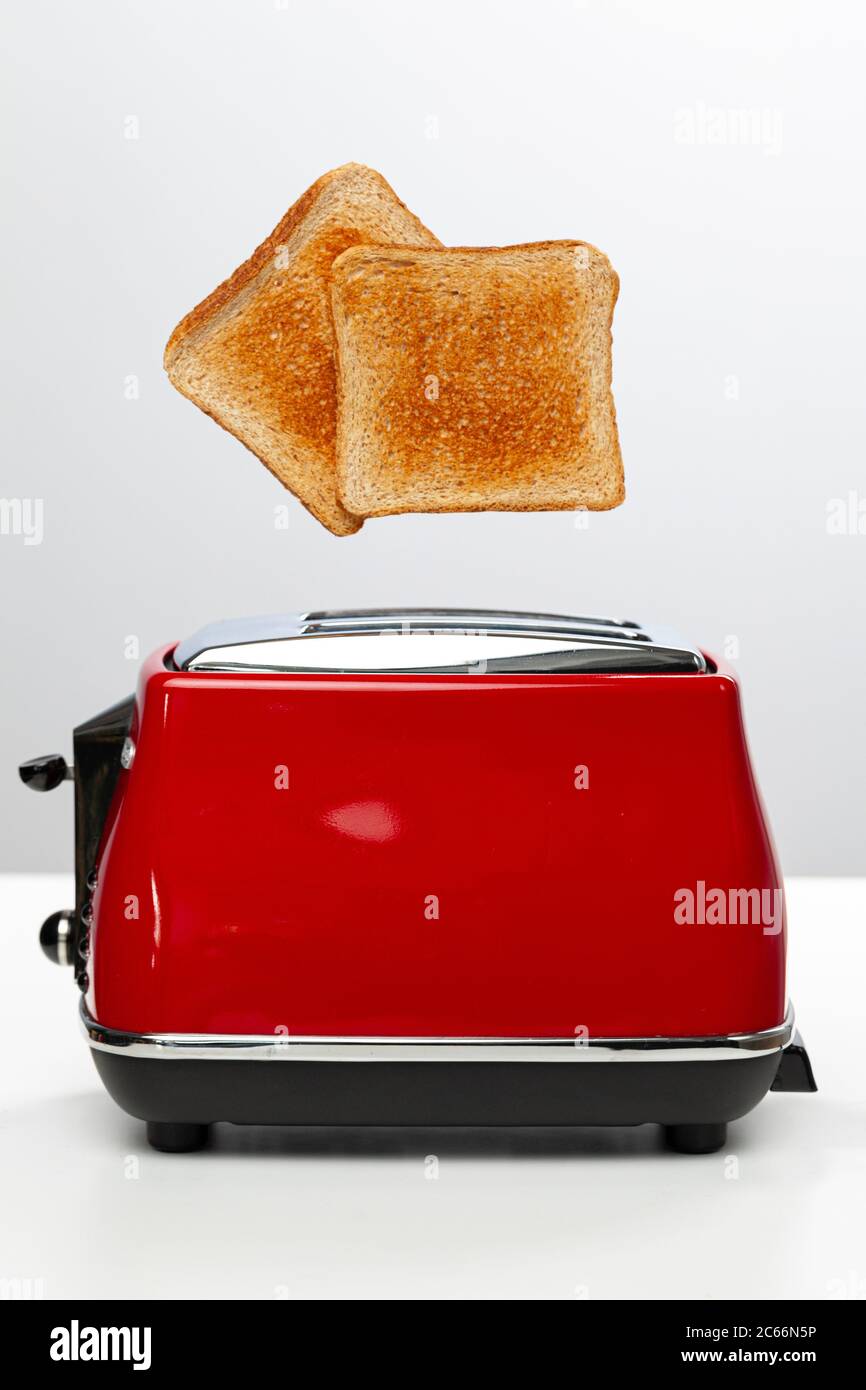 Two toasts jumping out of red toaster against white background Stock ...