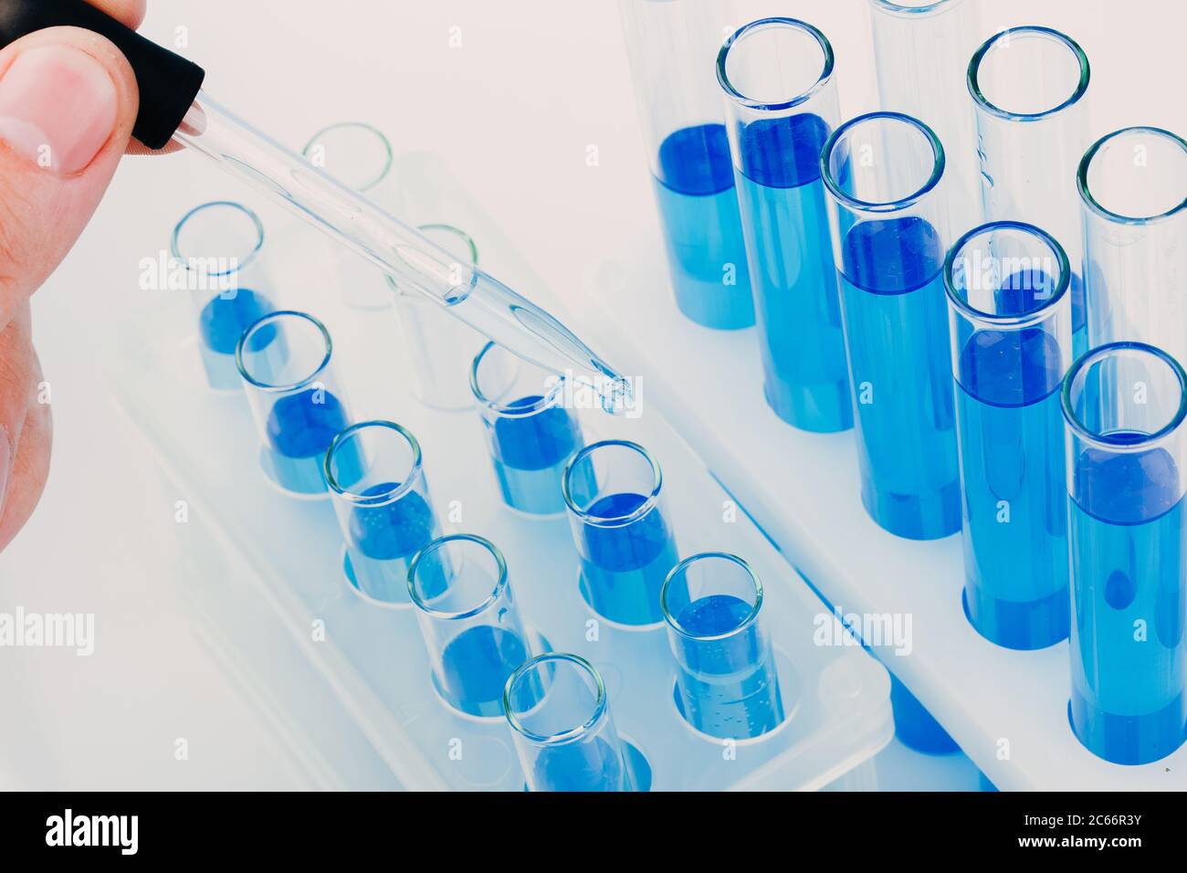 Laboratory glassware with a dropper dripping liquid into a test tube ...