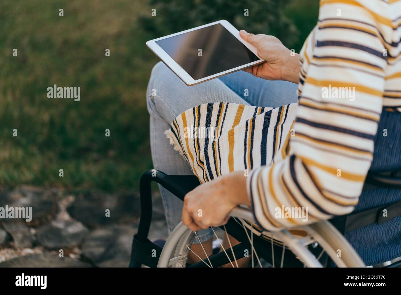 Fashionably dressed woman in a wheelchair with a modern tablet in hand ...