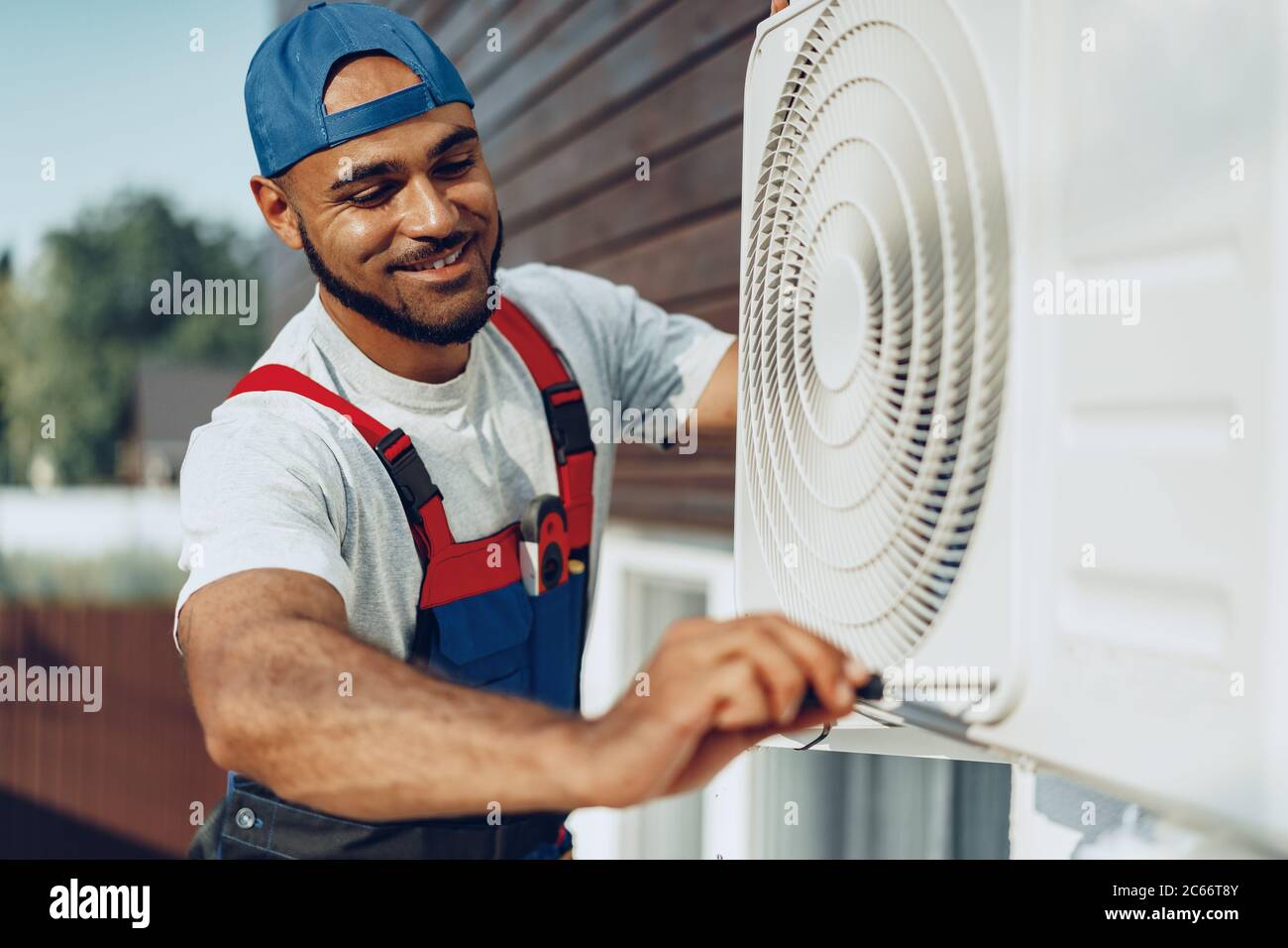 Young black man repairman checking an outside air conditioner unit ...