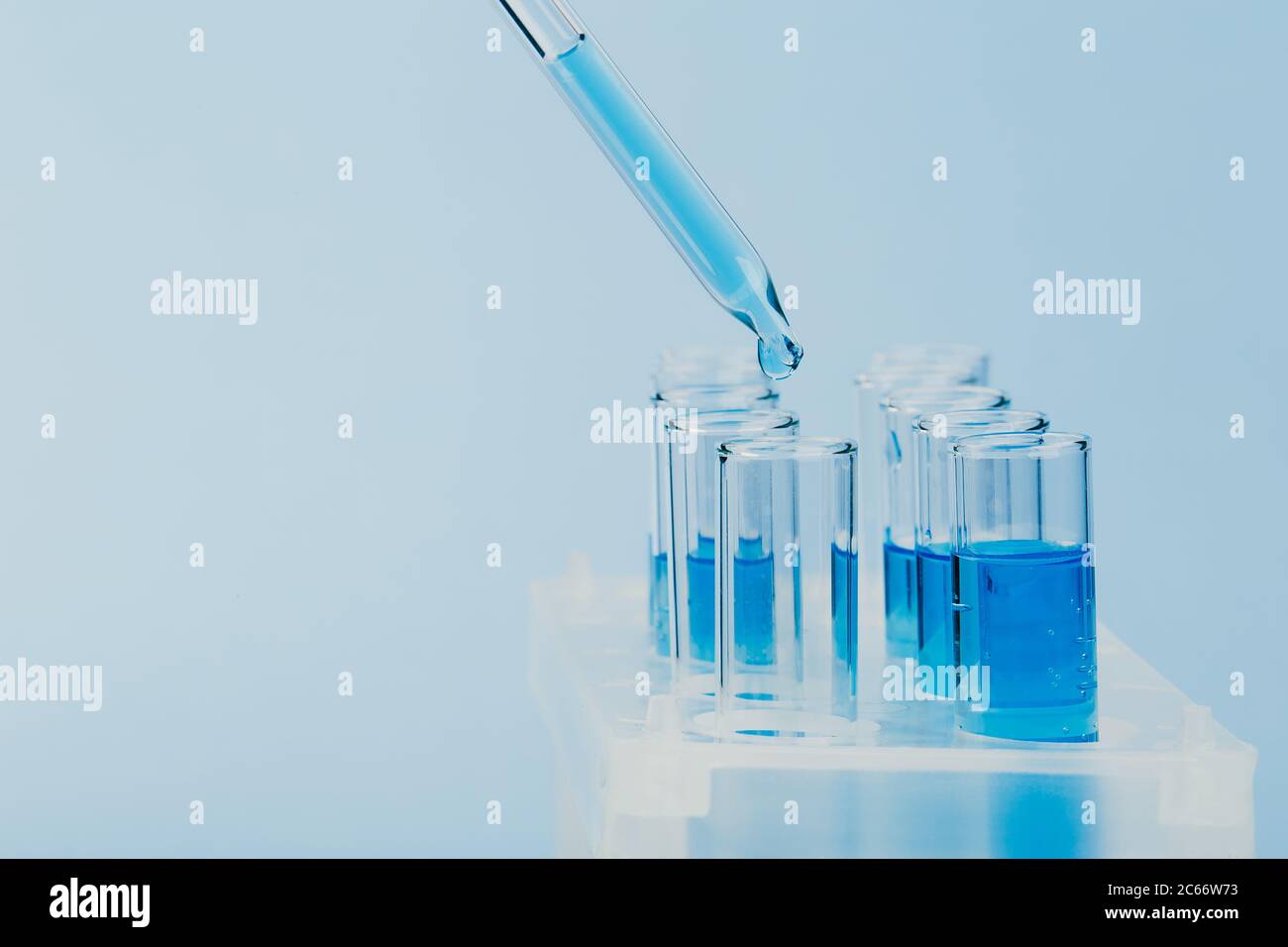 Laboratory glassware with a dropper dripping liquid into a test tube ...