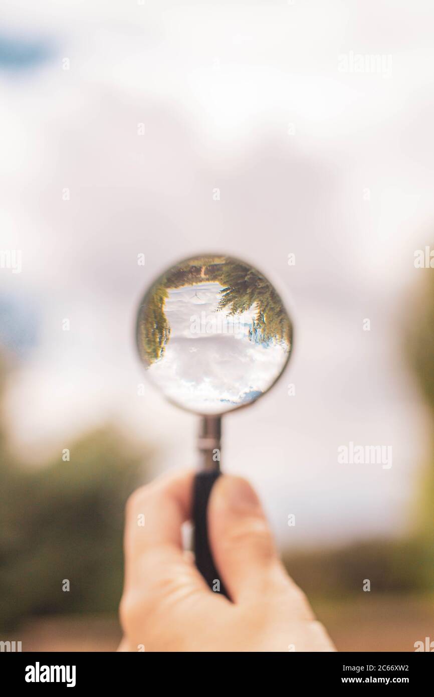 magnifying glass pointing at cloudy blue sky Stock Photo - Alamy