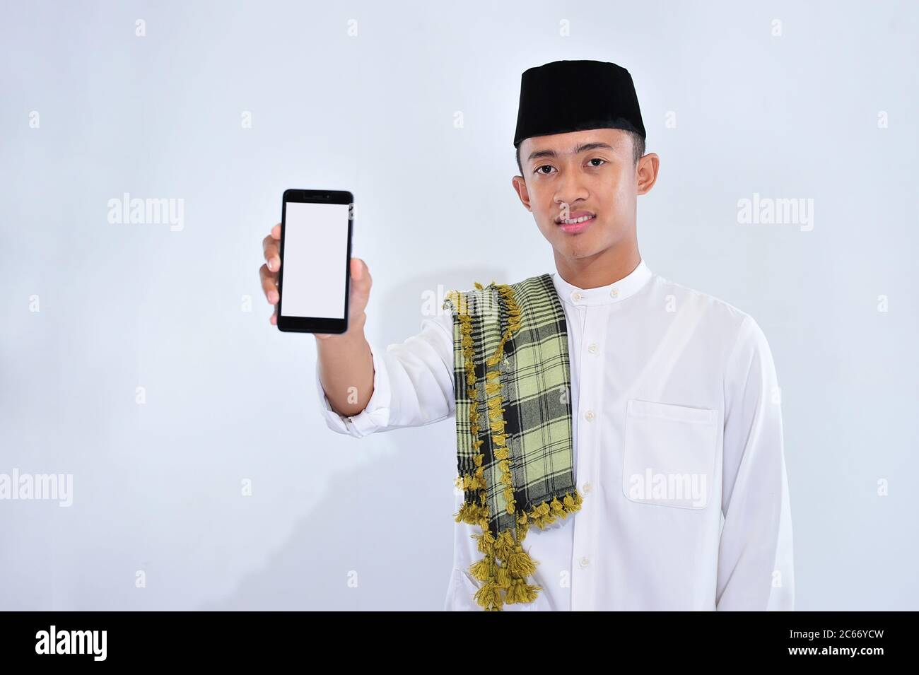 Portrait of a smiling young muslim man pointing at white screen mobile ...