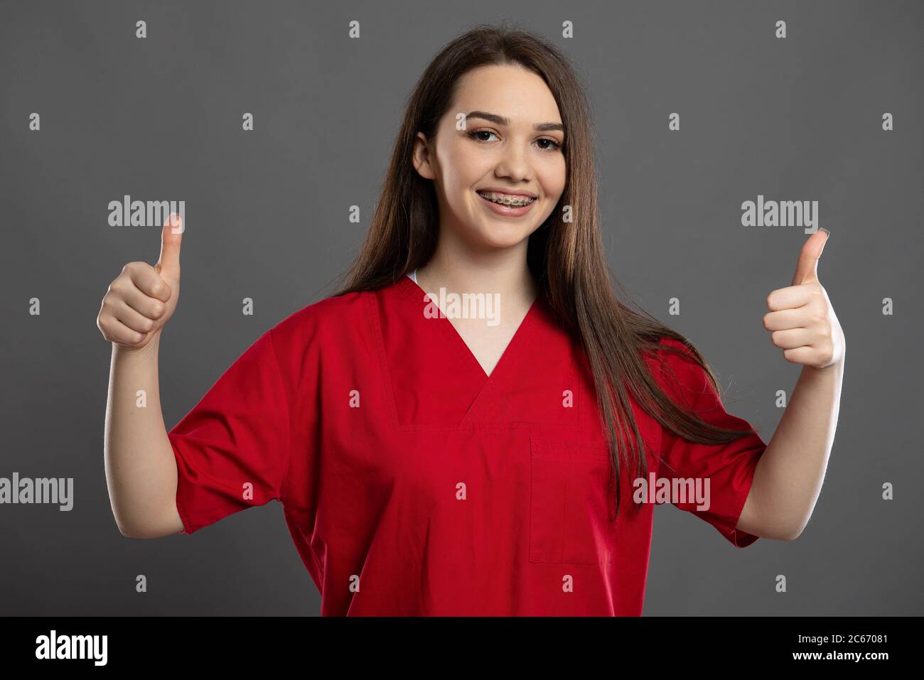 Cheeky young nurse smiling and giving two thumbs up wearing a pair of ...