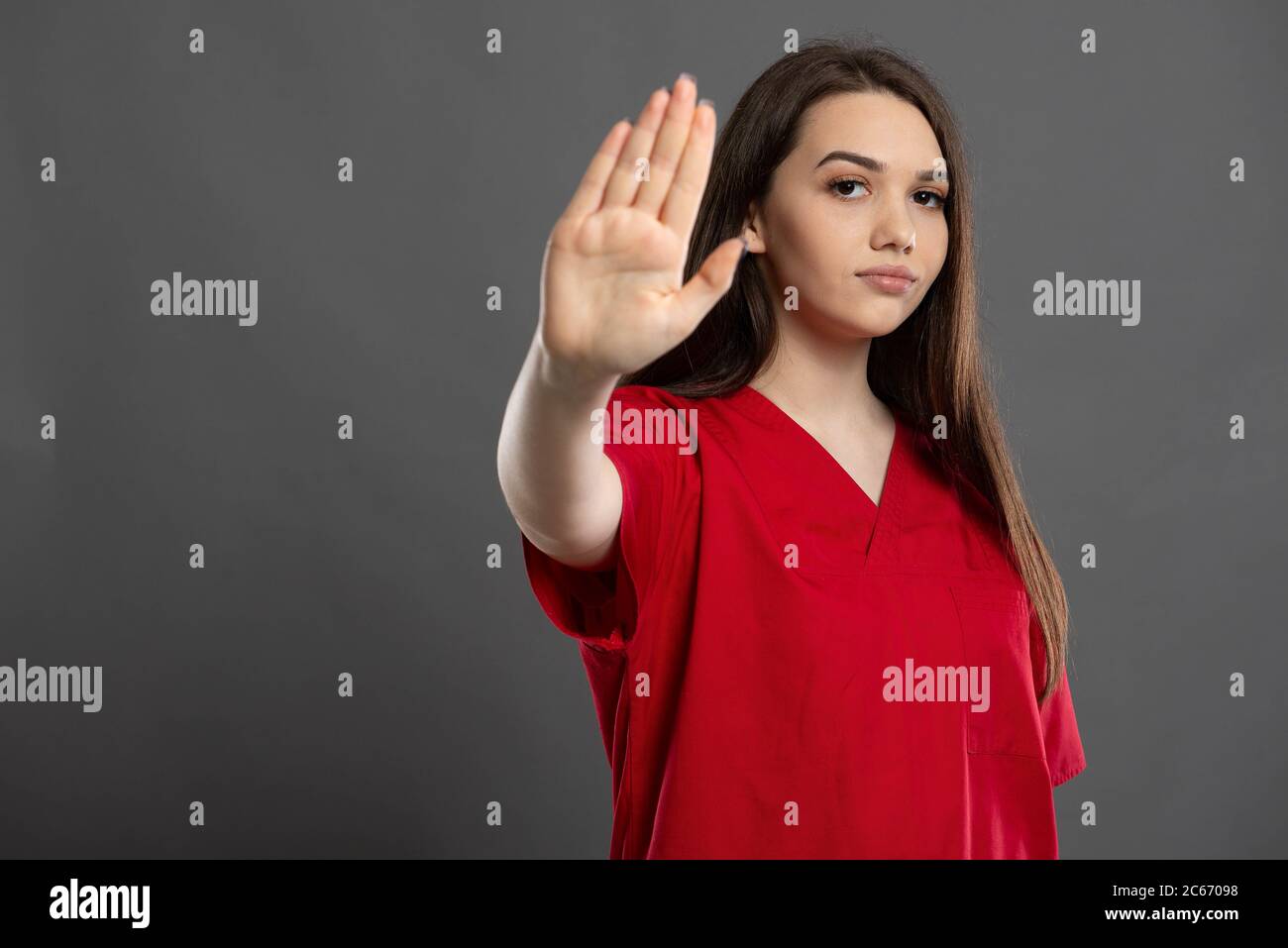 Beautiful young nurse showing stop sign to the camera wearing a pair of ...