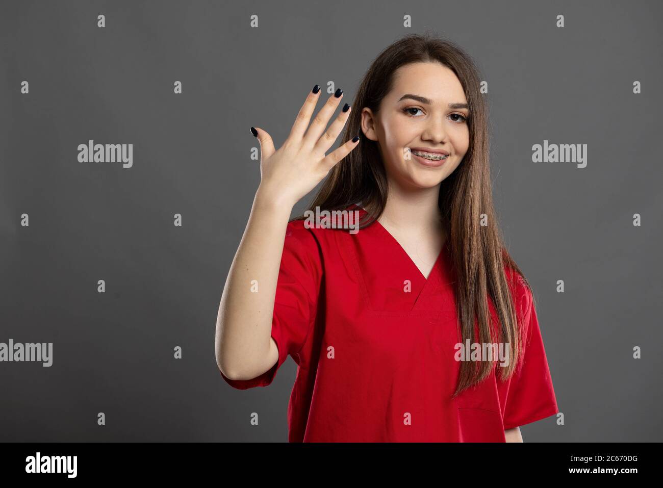 Beautiful young smiling nurse counting to five and wearing red scrubs ...