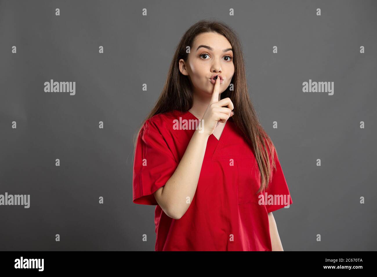 Portrait of a beautiful long hair young nurse asking for silence by ...