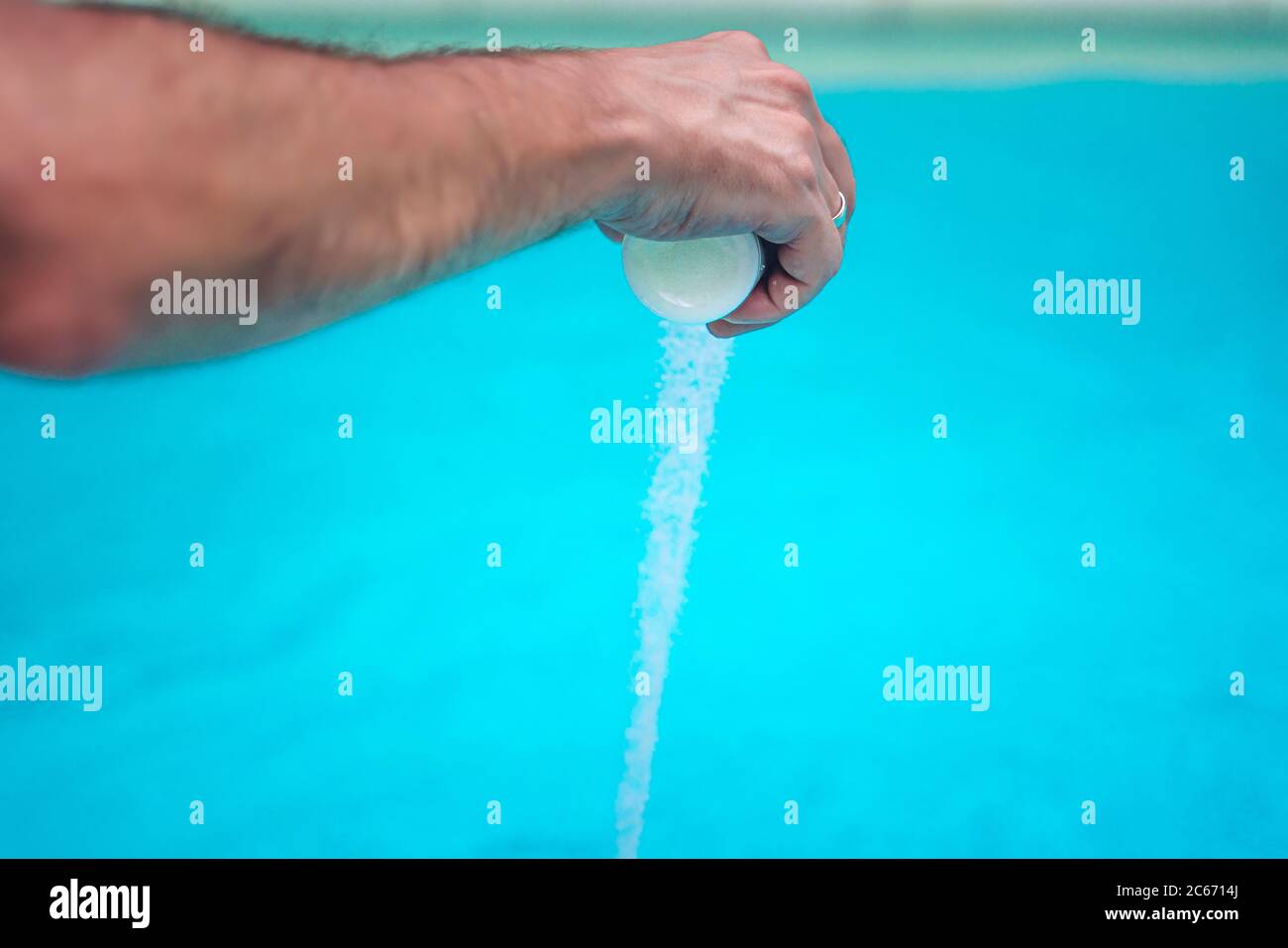 Person cleaning and chlorinating the pool on a hot summer afternoon, is ...