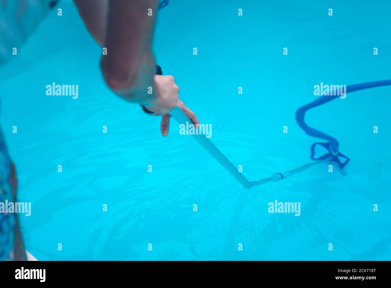 Person cleaning and chlorinating the pool on a hot summer afternoon, is ...