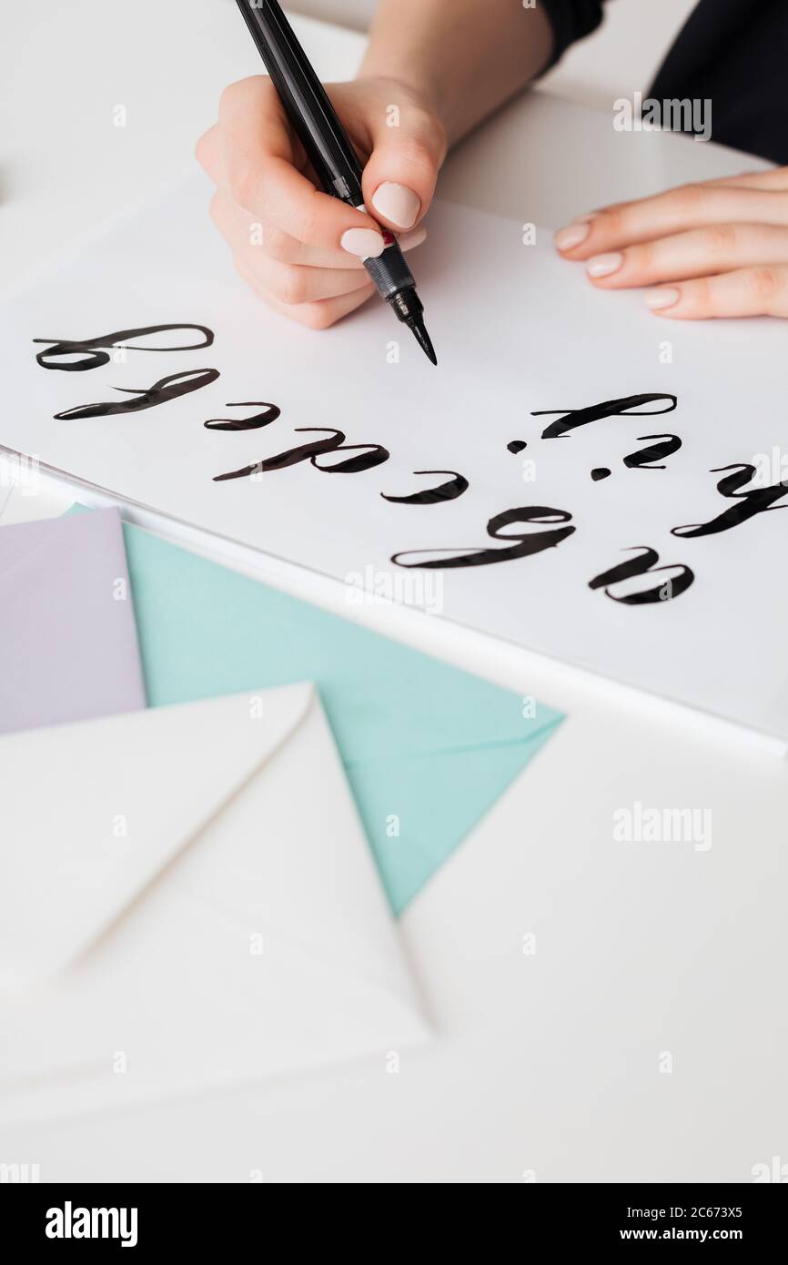 Close up photo of young woman hands writing alphabet on paper on desk ...