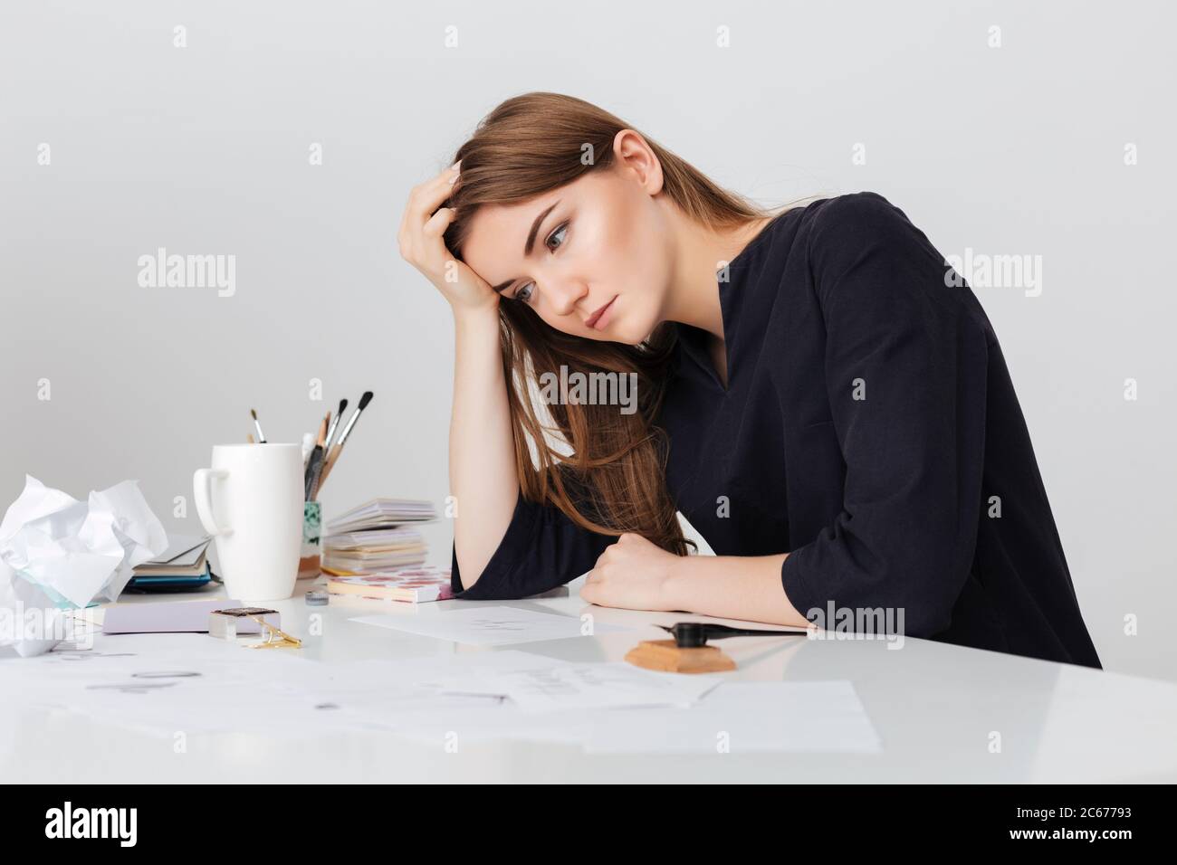 Portrait of young nice lady sitting at the white desk and leaning head ...