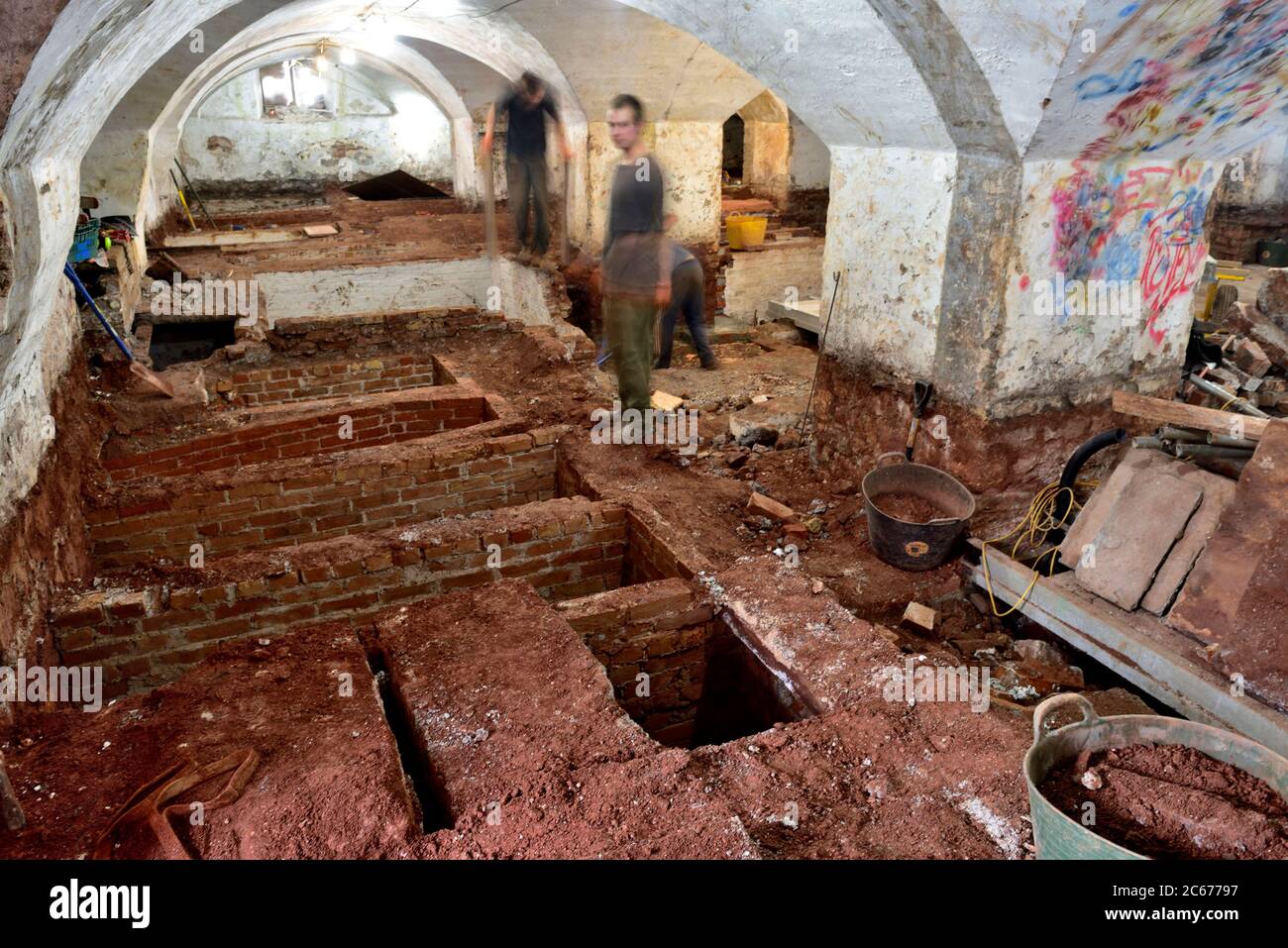 Workmen checking stones capping on tombs with coffin in crypt of ...