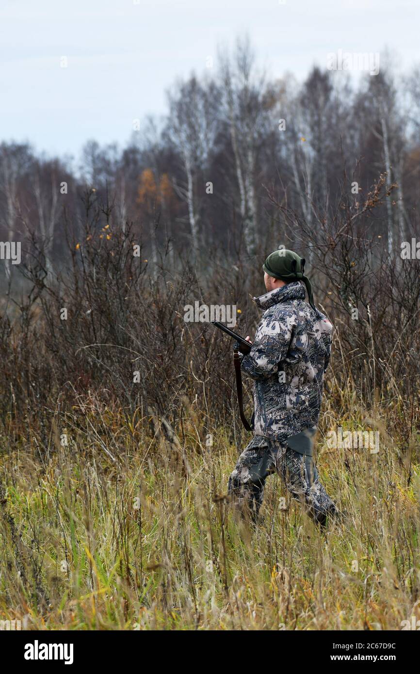 A hunter with the rifle going in field at dawn. Bird hunting Stock ...