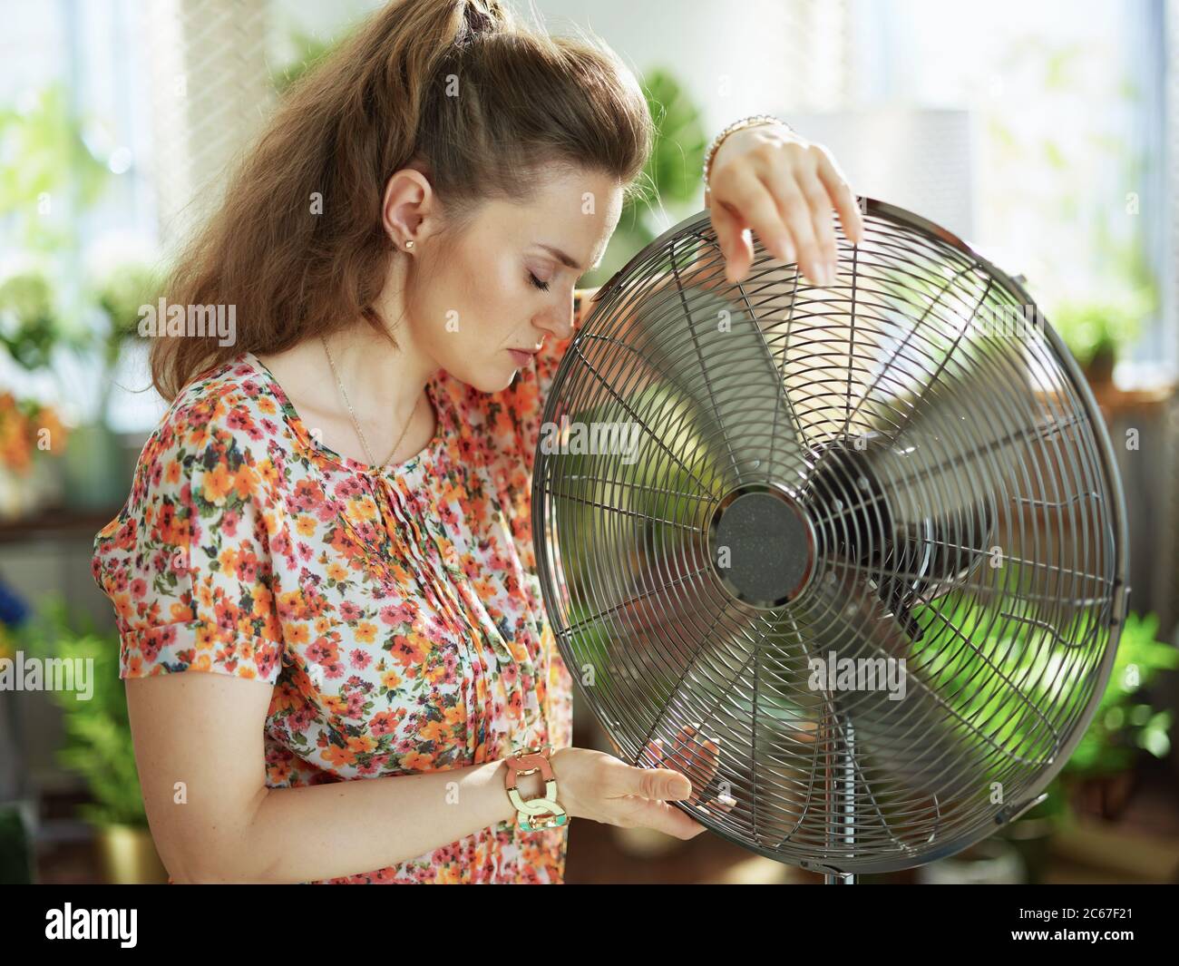 Summer heat. sad modern female in floral blouse at modern home in sunny ...