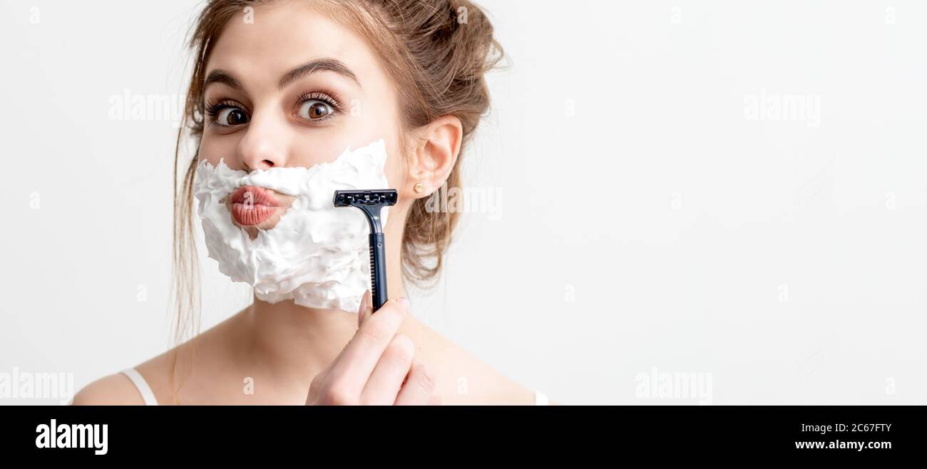 Beautiful young caucasian woman shaving her face by razor on white ...