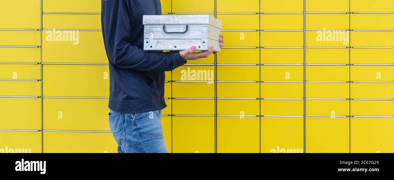 Parcel holding in hands and sending using yellow self-service post ...