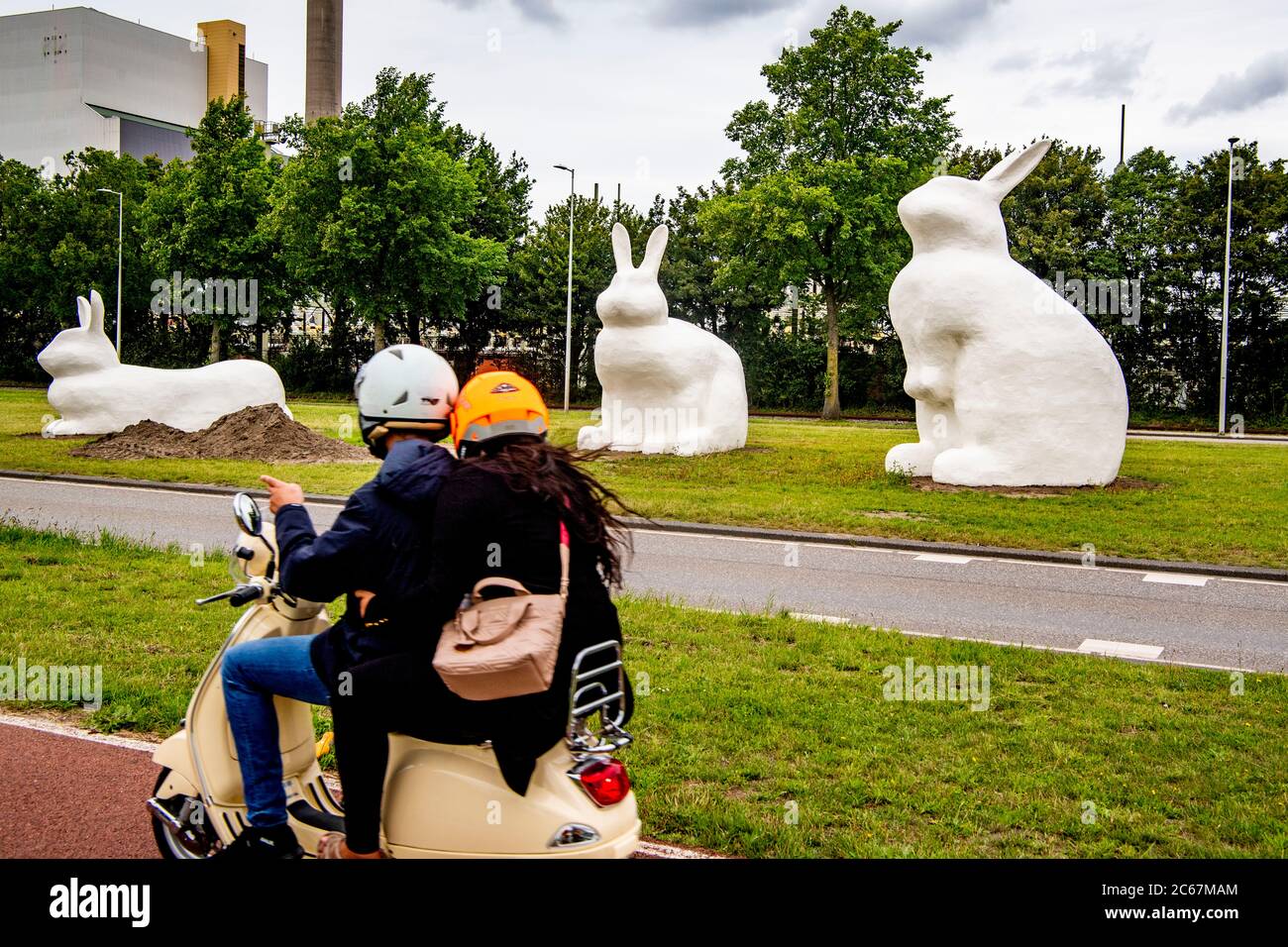 A couple rides past the three giant rabbit statues (Berm Bunnies ...