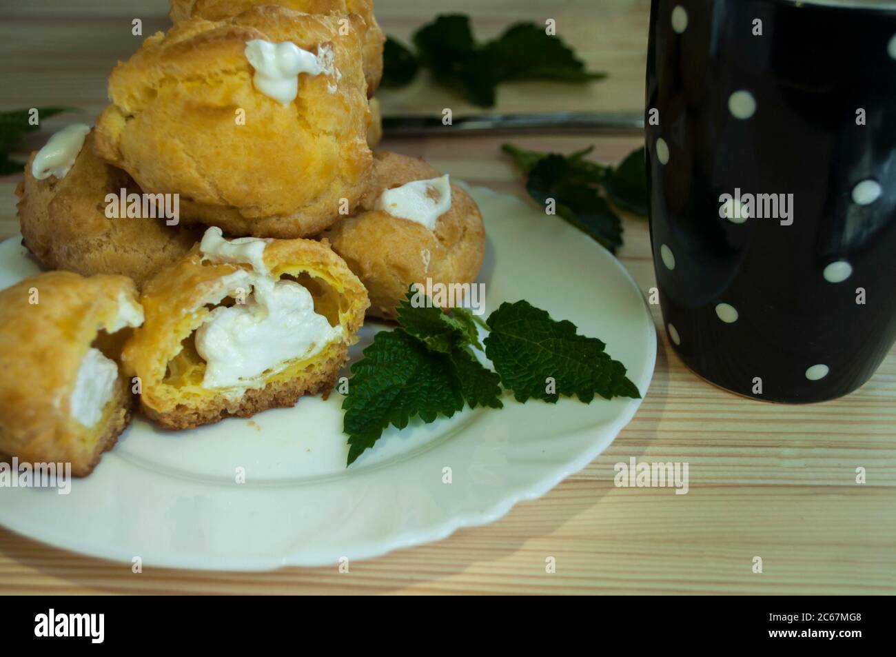 Portion of eclairs filled with whipped cream with a cup of tea on a ...