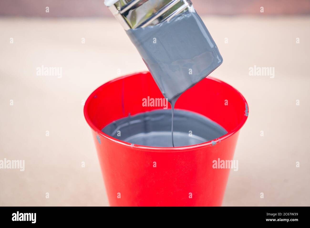 Close up of dipping brush into grey paint outside. Home renovation ...