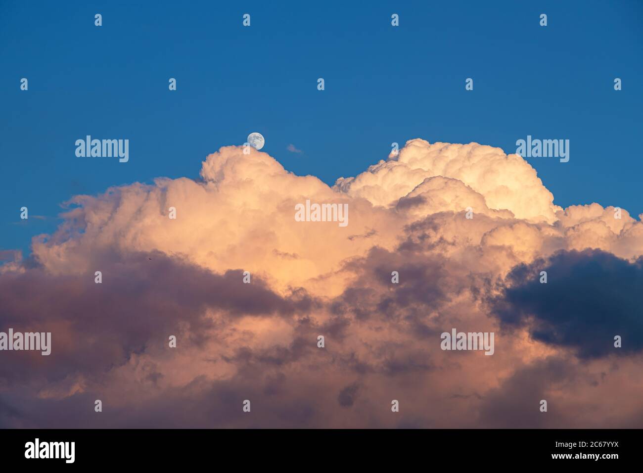 Small moon above large, storm cloud, during the day Stock Photo - Alamy