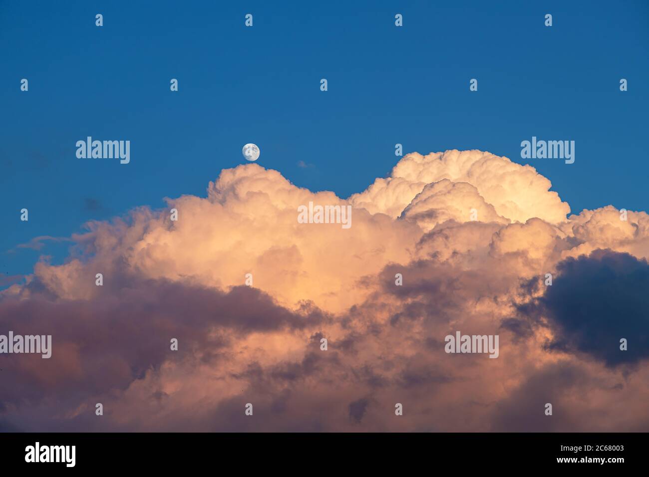 Small moon above large, storm cloud, during the day Stock Photo - Alamy
