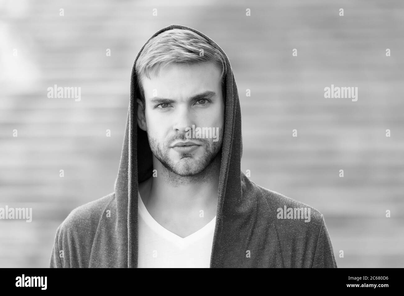 Popular street style. Handsome man with hood standing urban background ...