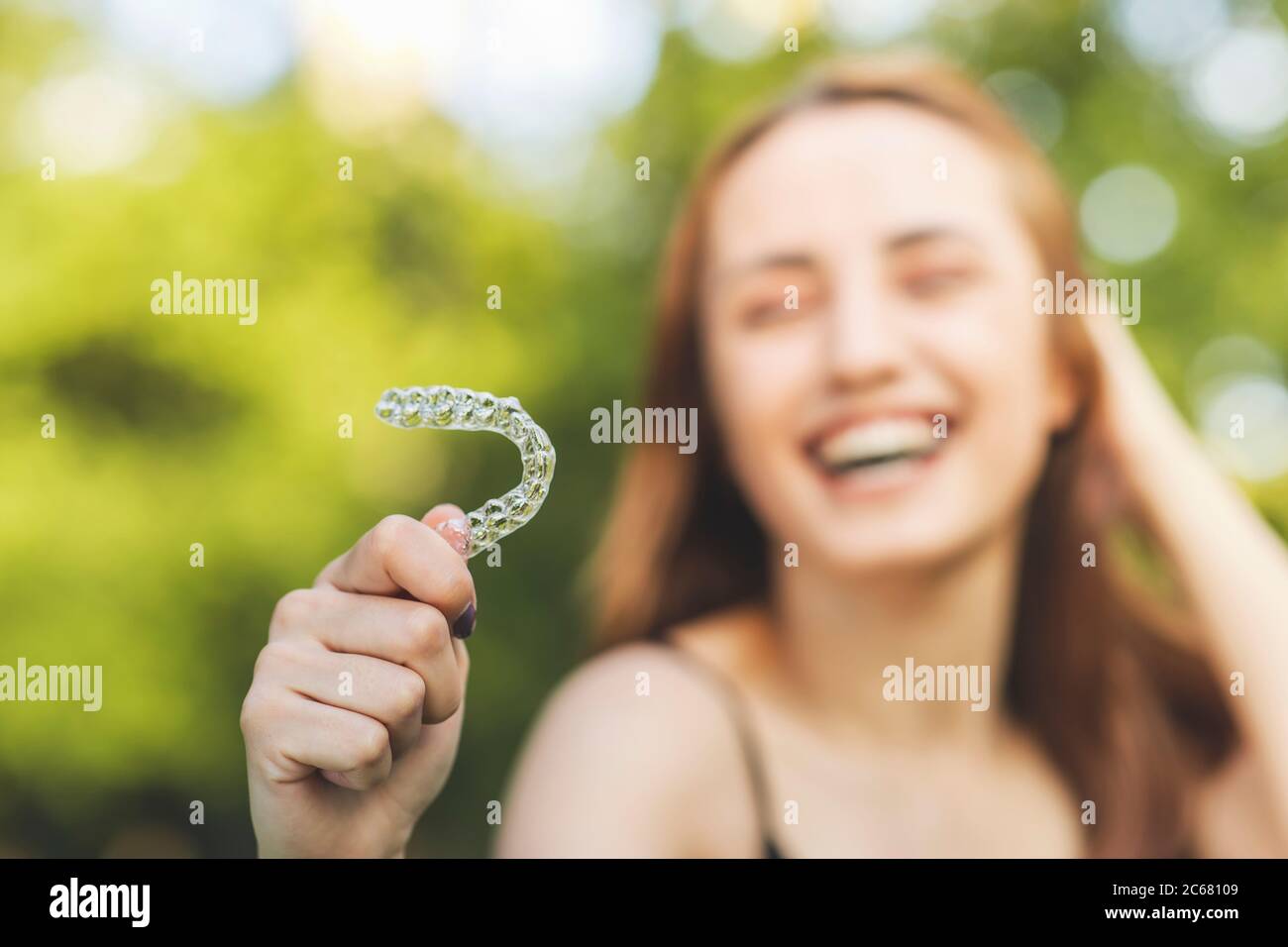 Beautiful smiling Turkish woman is holding an invisalign bracer with ...