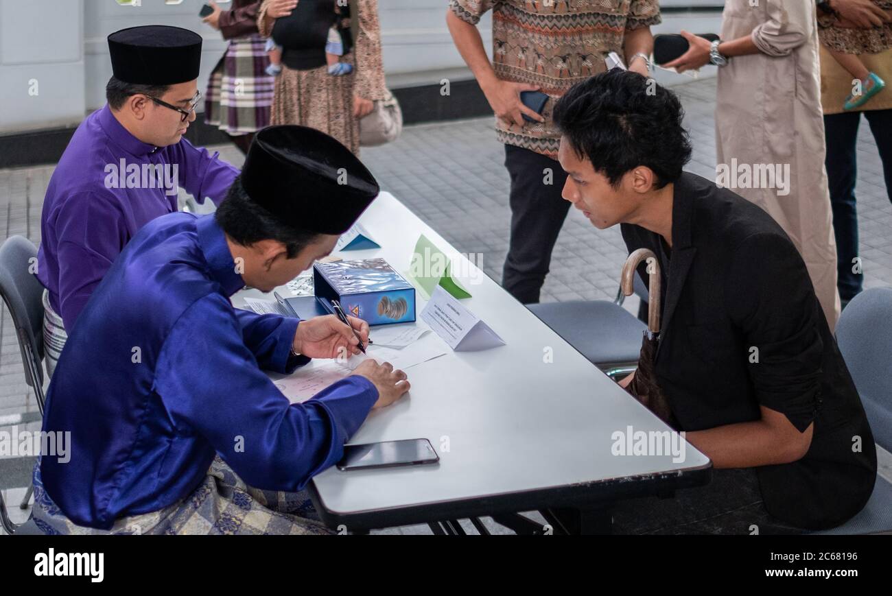 Muslim paying the compulsory zakat (alms giving) during Eid Celebration ...