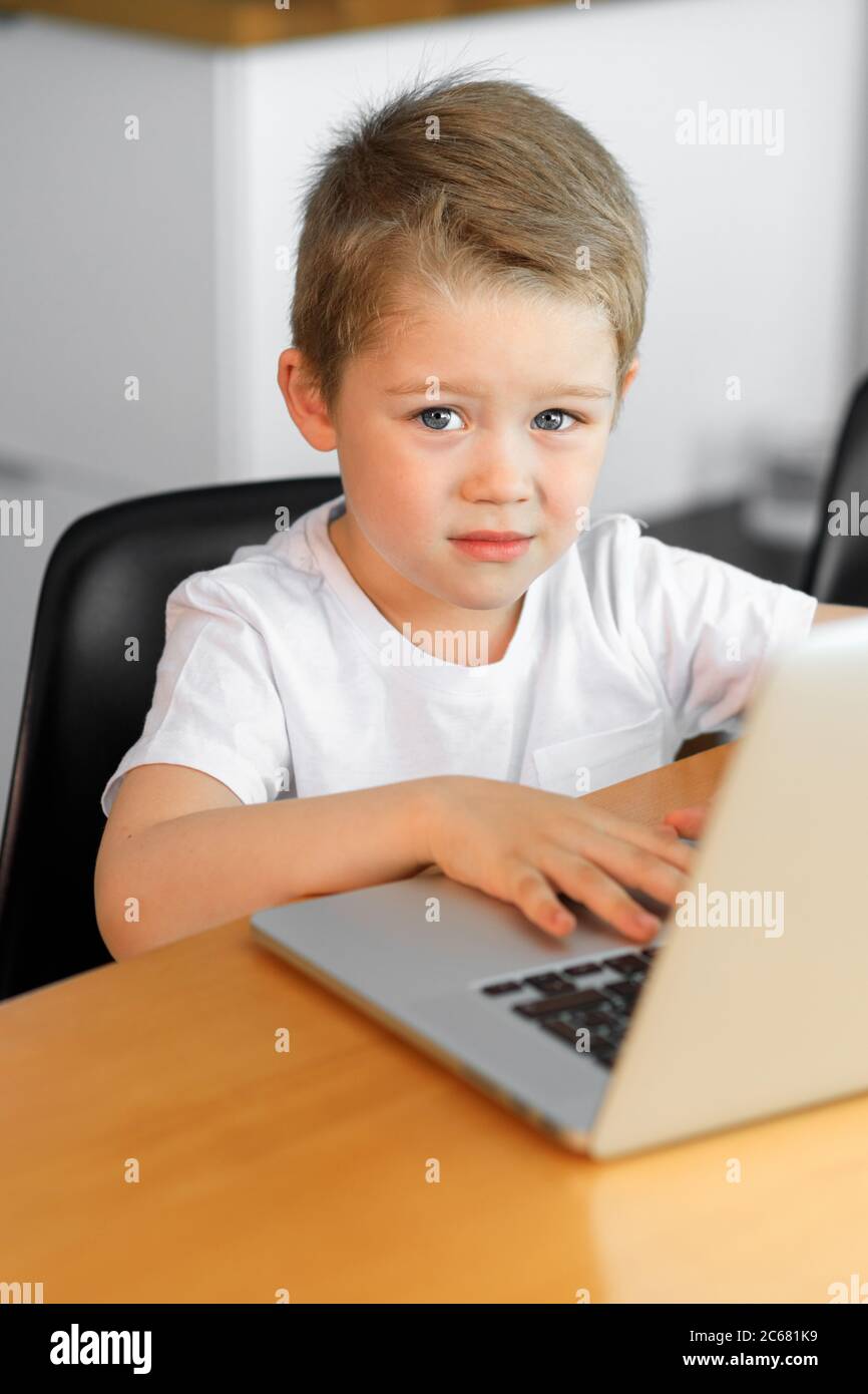 A young boy using a laptop computer sitting on top of a table at home ...