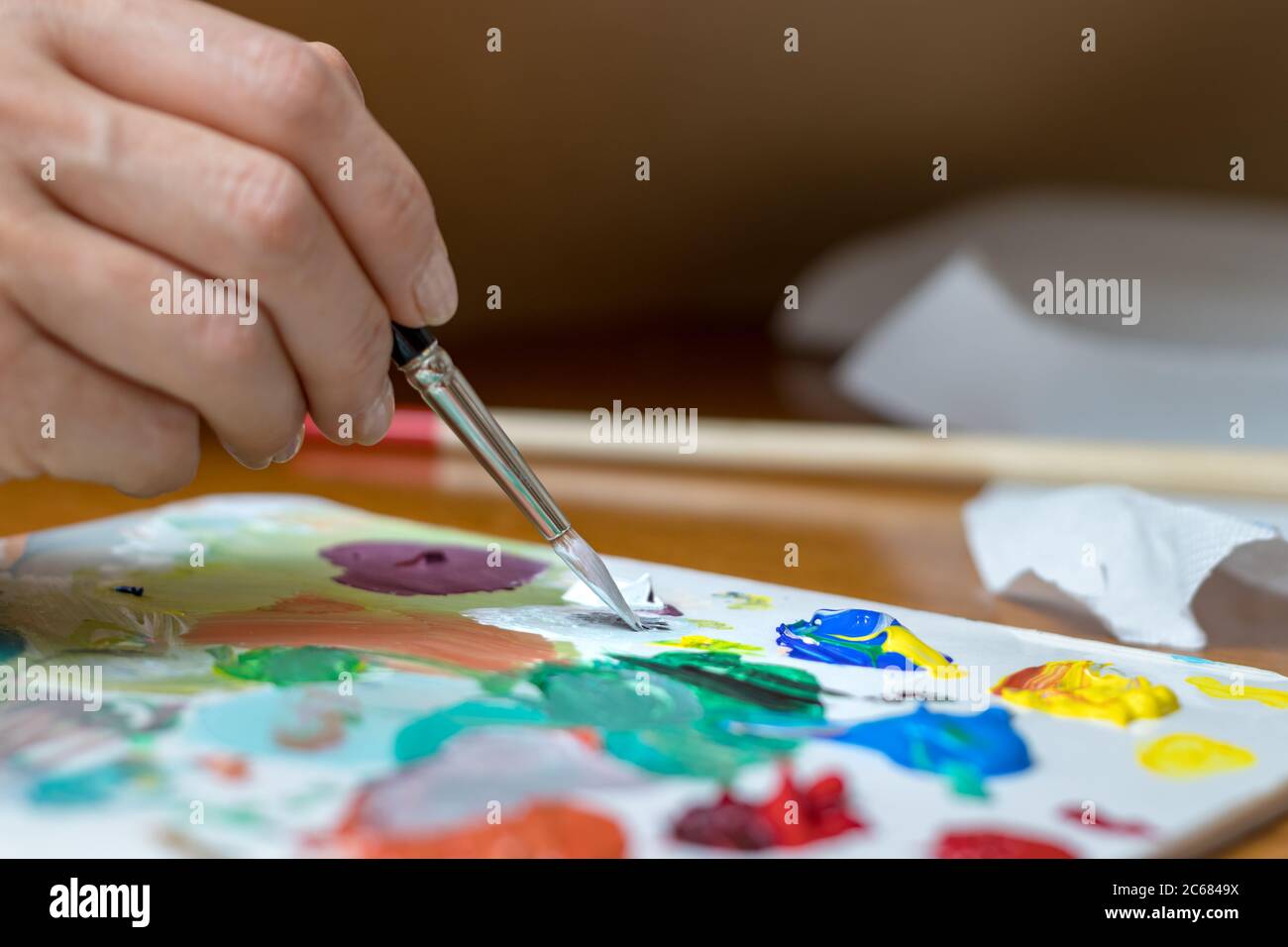 Female artist hand mixing colors with a paintbrush on a color palette ...