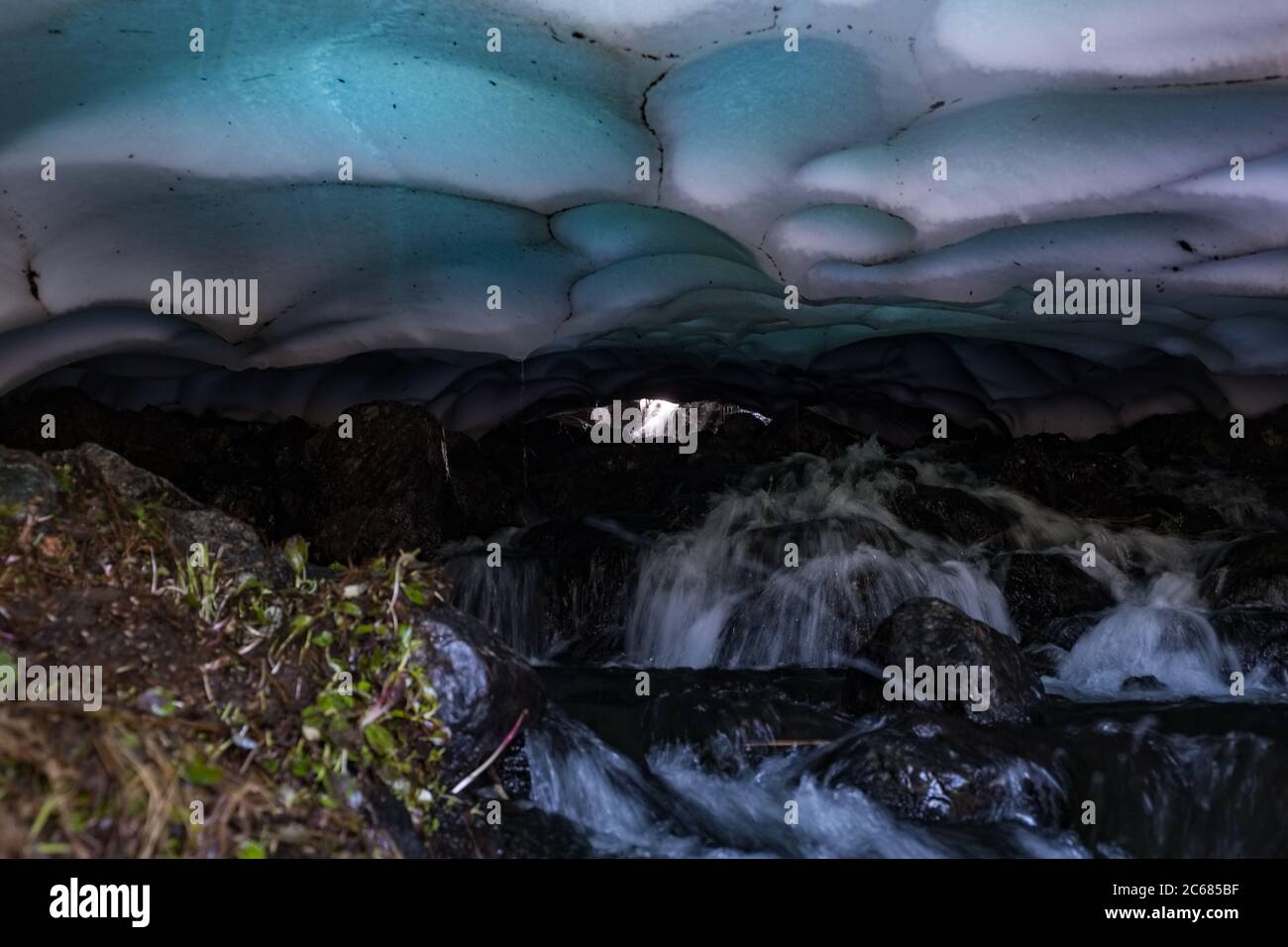 Underside of some melting snow pack carved by a stream Stock Photo - Alamy