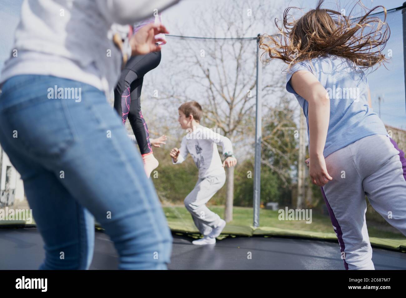 Kids jumping on trampoline while having fun on summer day in park ...