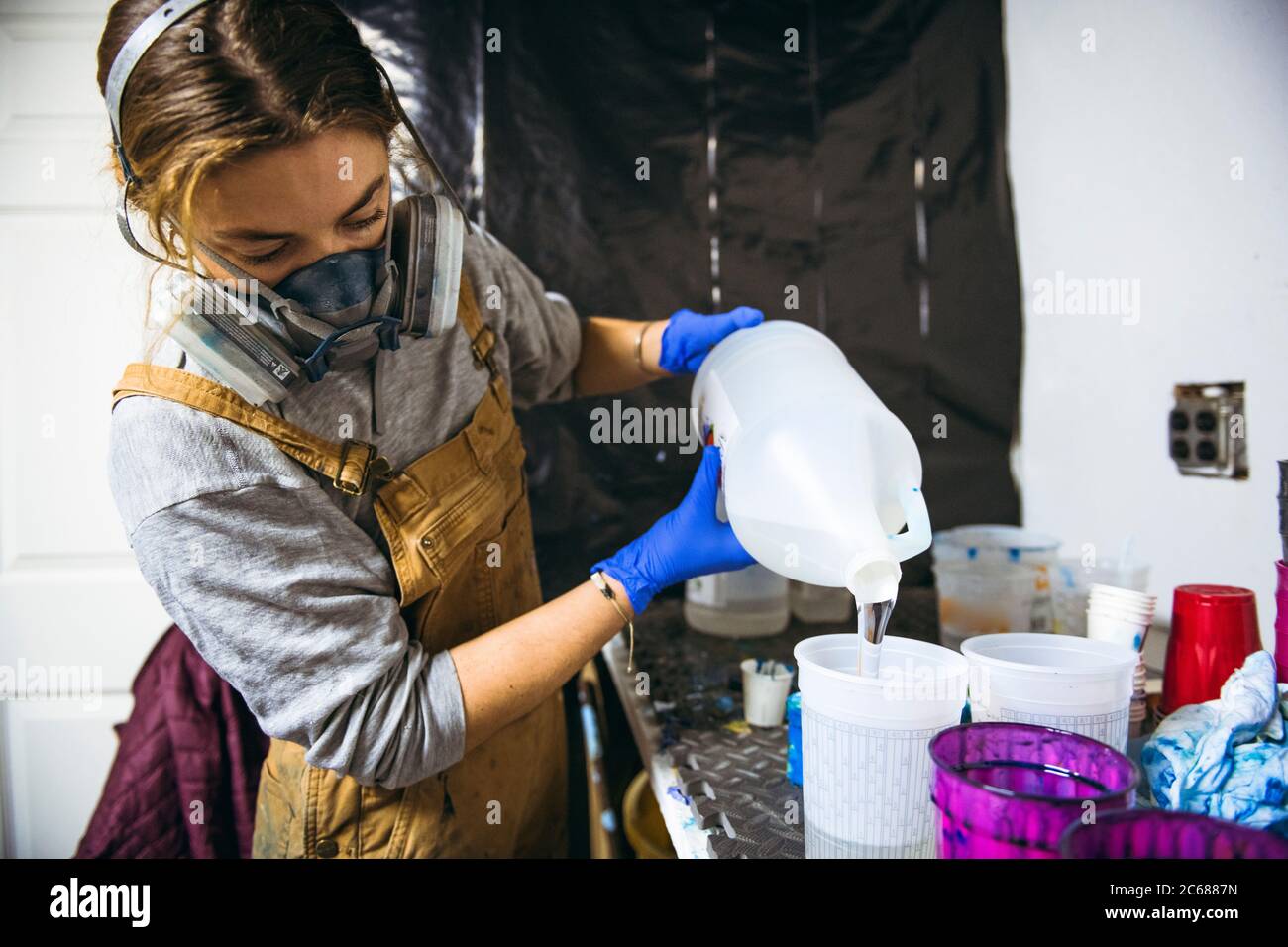 Female resin artist mixing and pouring with respirator mask Stock Photo ...