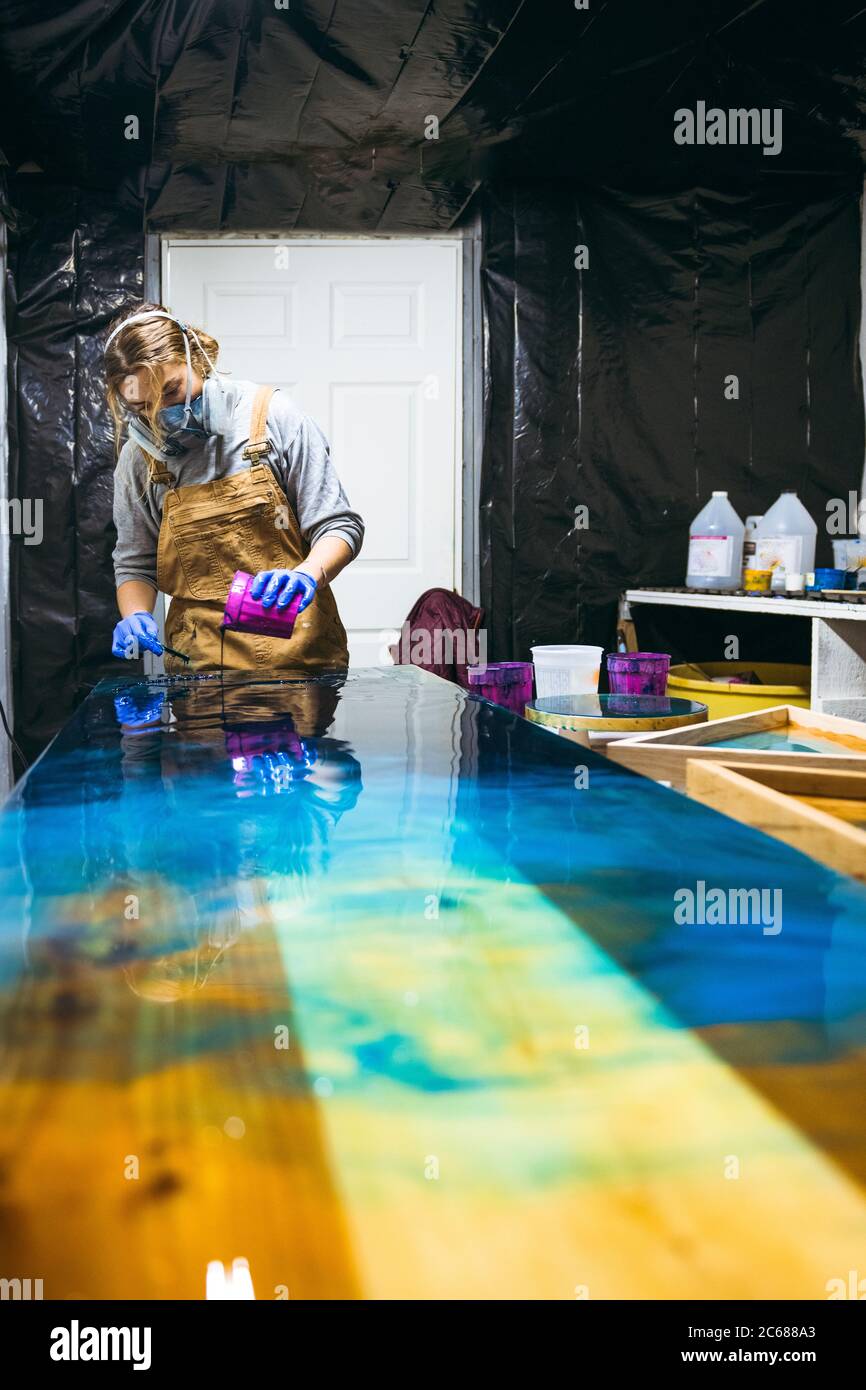 Female resin artist pouring resin tint onto artwork Stock Photo - Alamy
